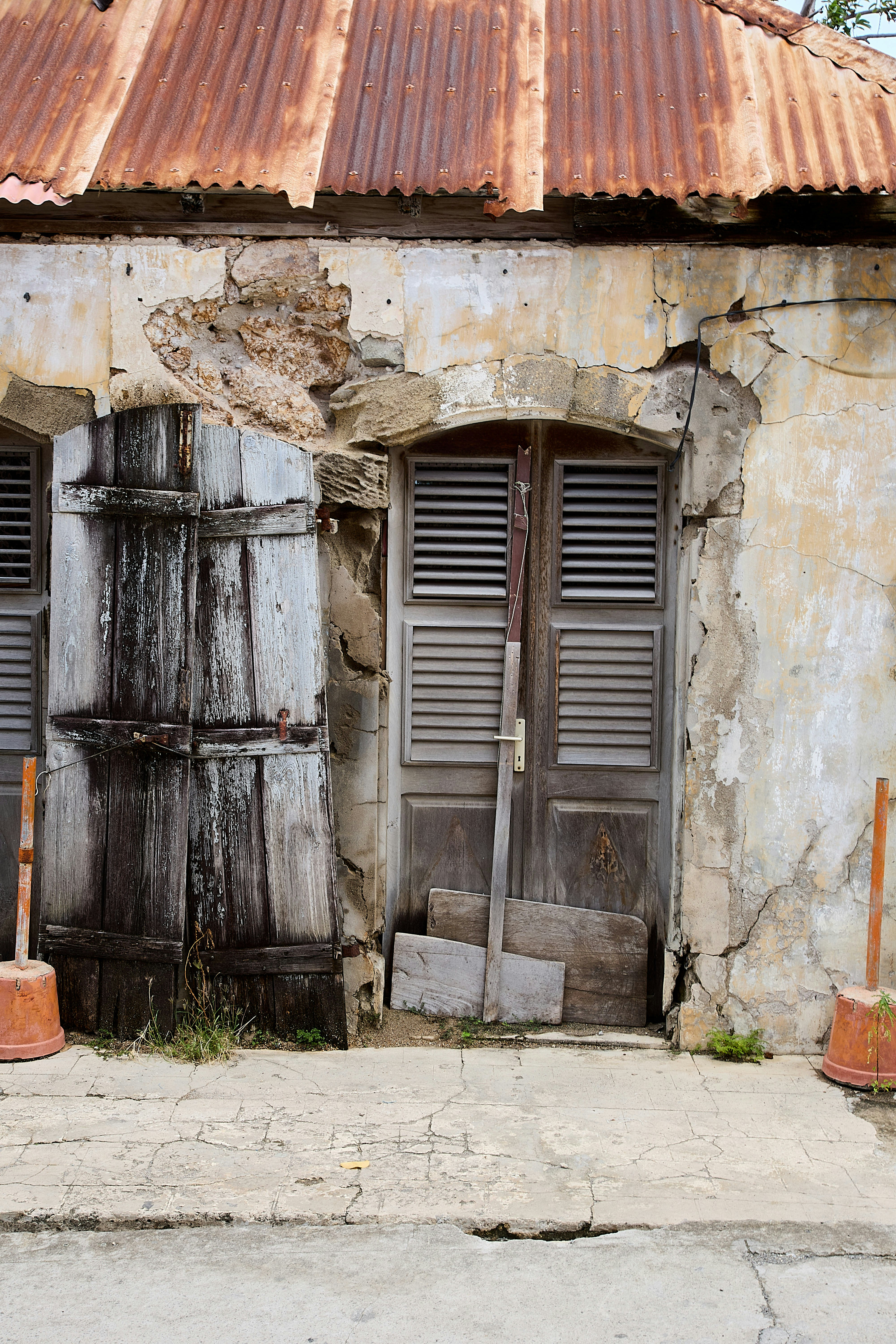 Weathered Doorway Amid Crumbling Wall and Corrugated Roofing