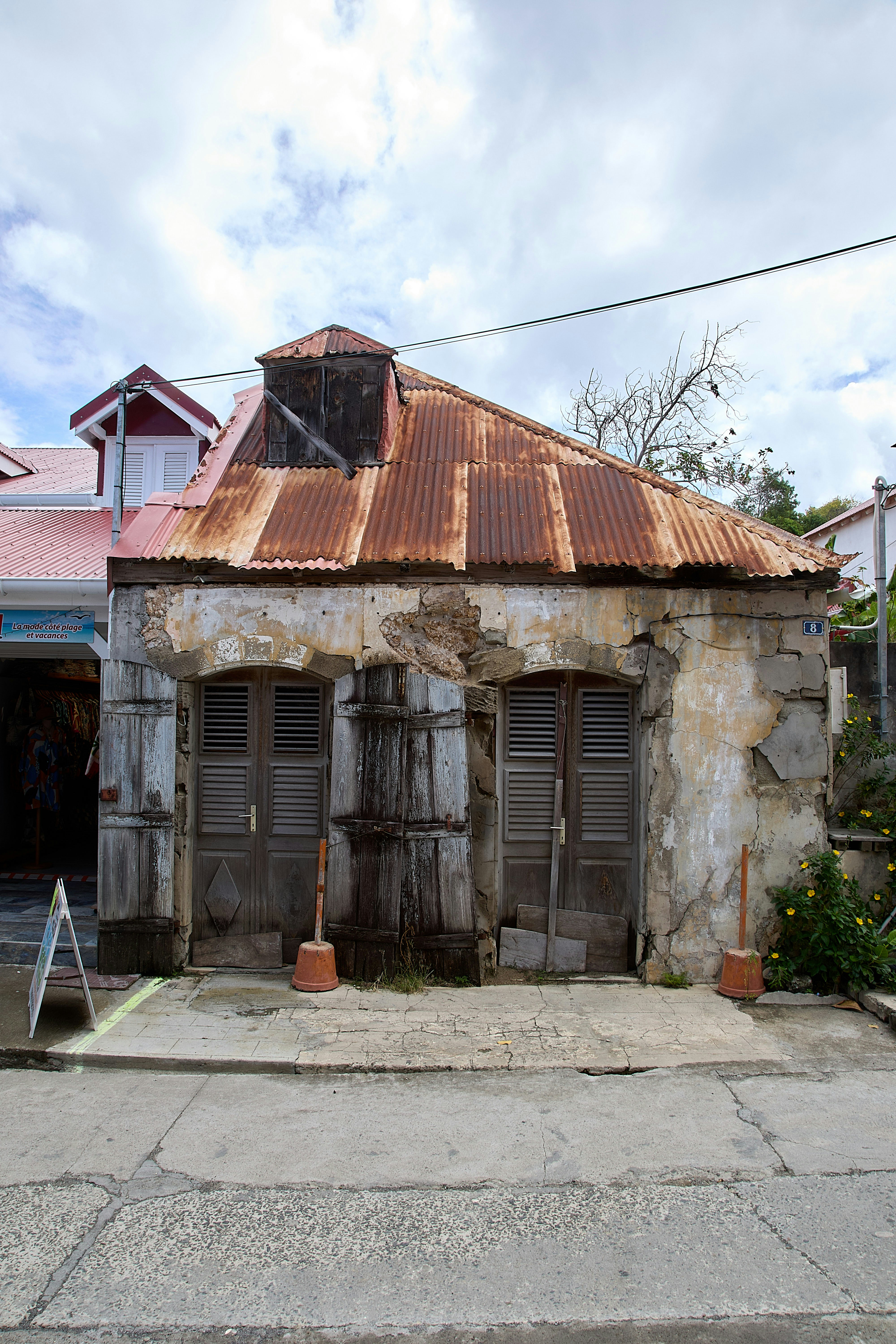 Rust and Stucco: A Weathered Shopfront Under a Corrugated Roof