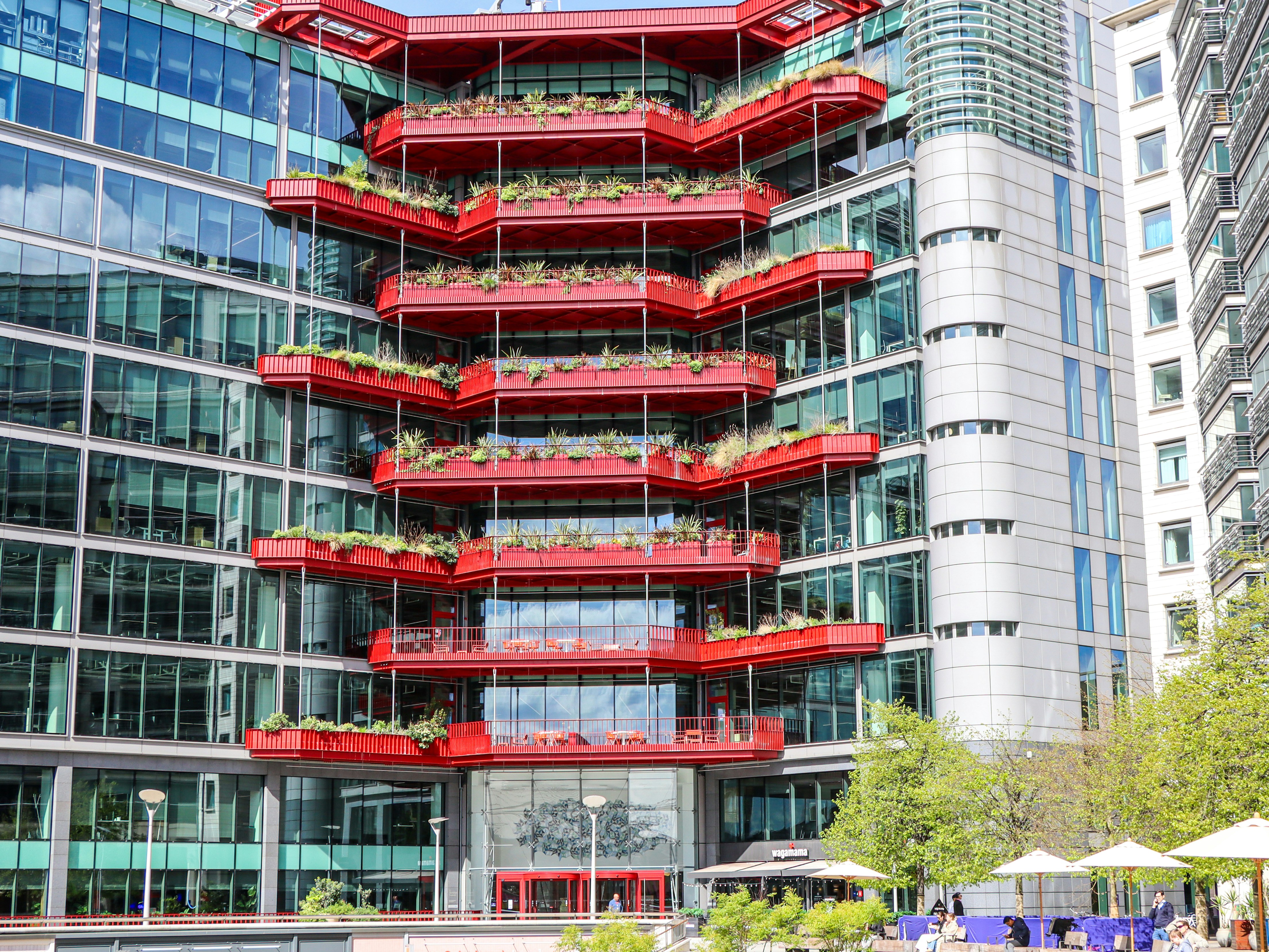 Urban Balcony Cascade: Red Terraces Along a Glass Front