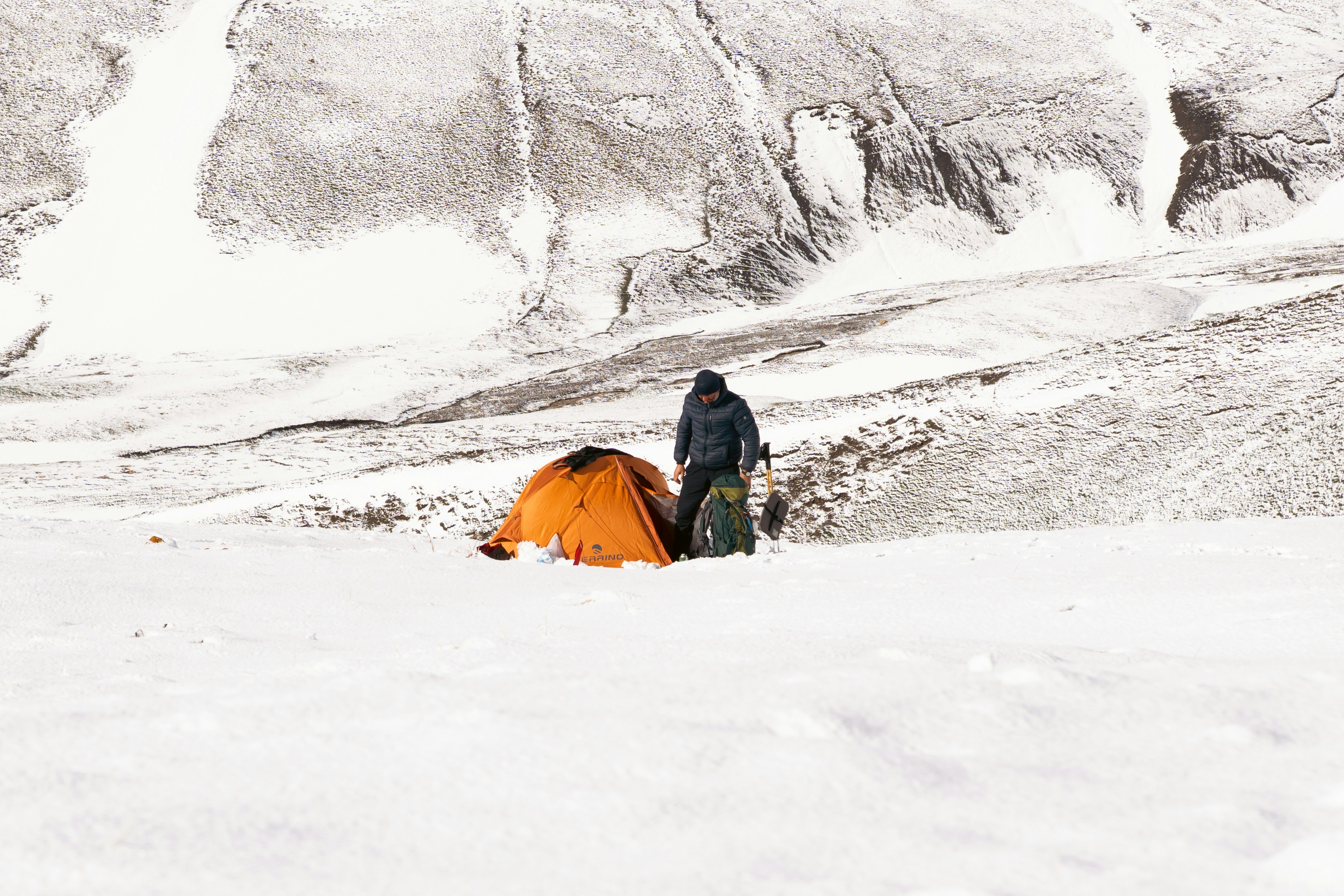 Cold Camp Under Snow-Capped Slopes: A Lone Climber and Orange Tent