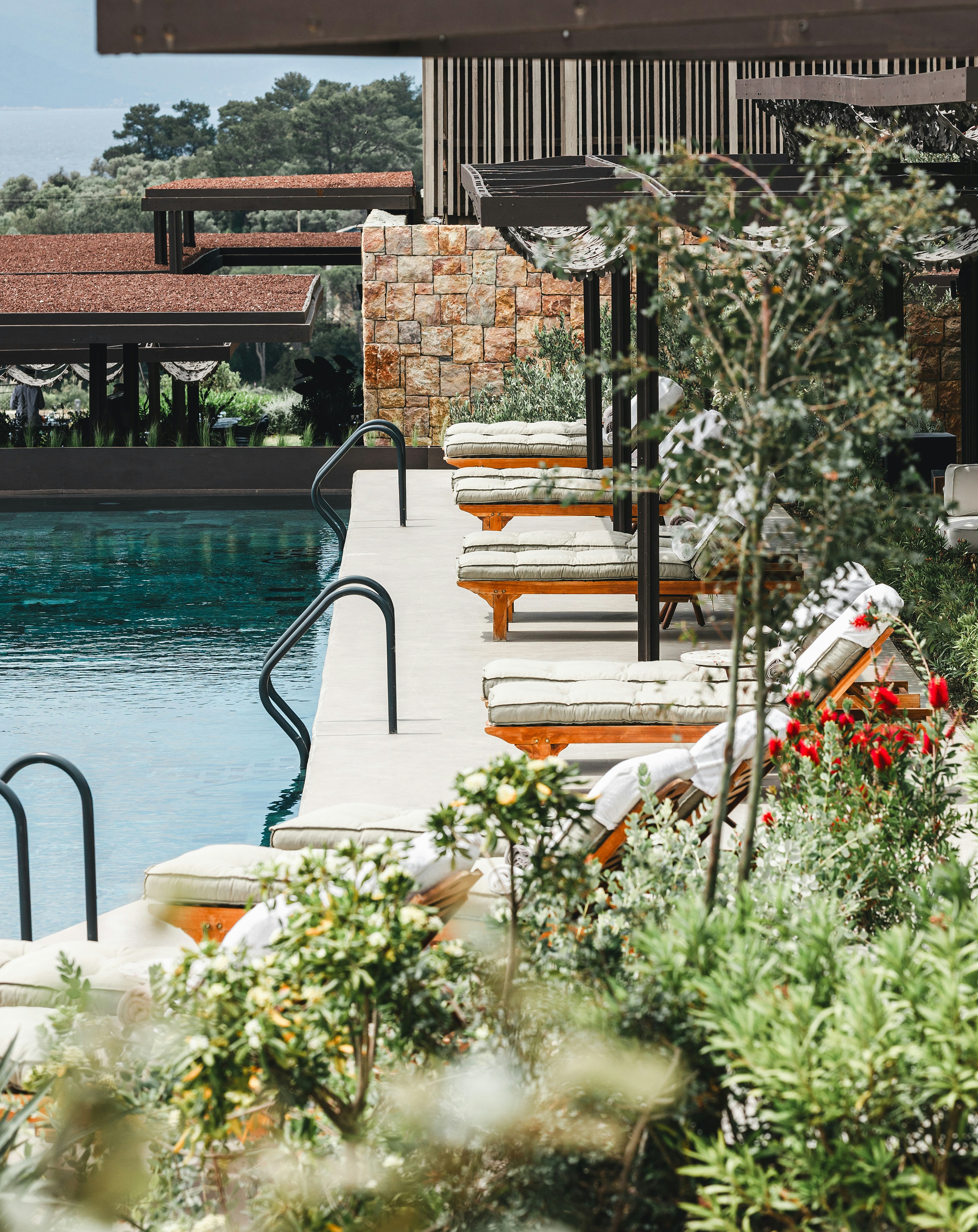Poolside Oasis: Loungers, Stone Wall, and lush landscaping
