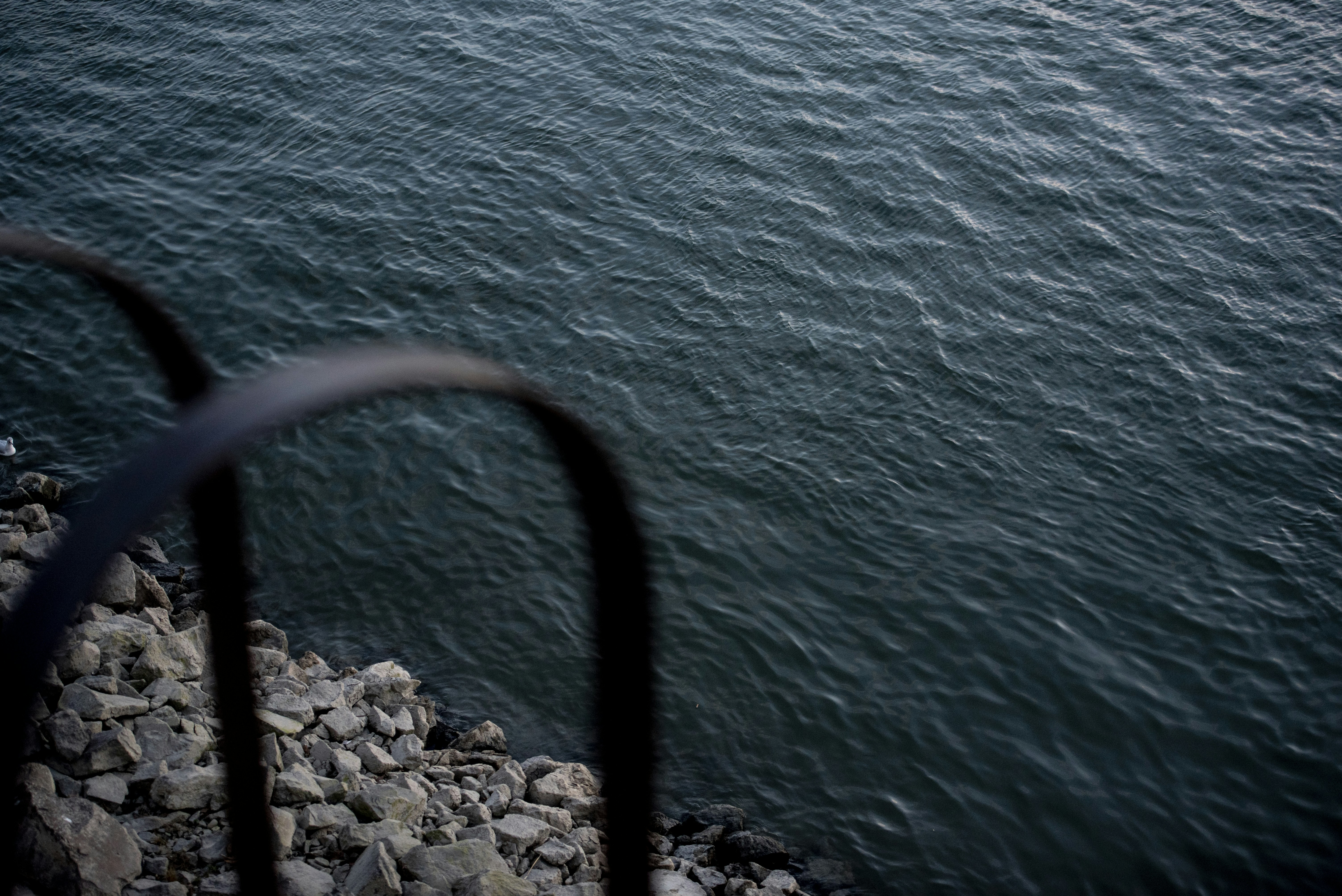 Rugged shoreline over calm sea: a quiet ascent from rocky breakwater