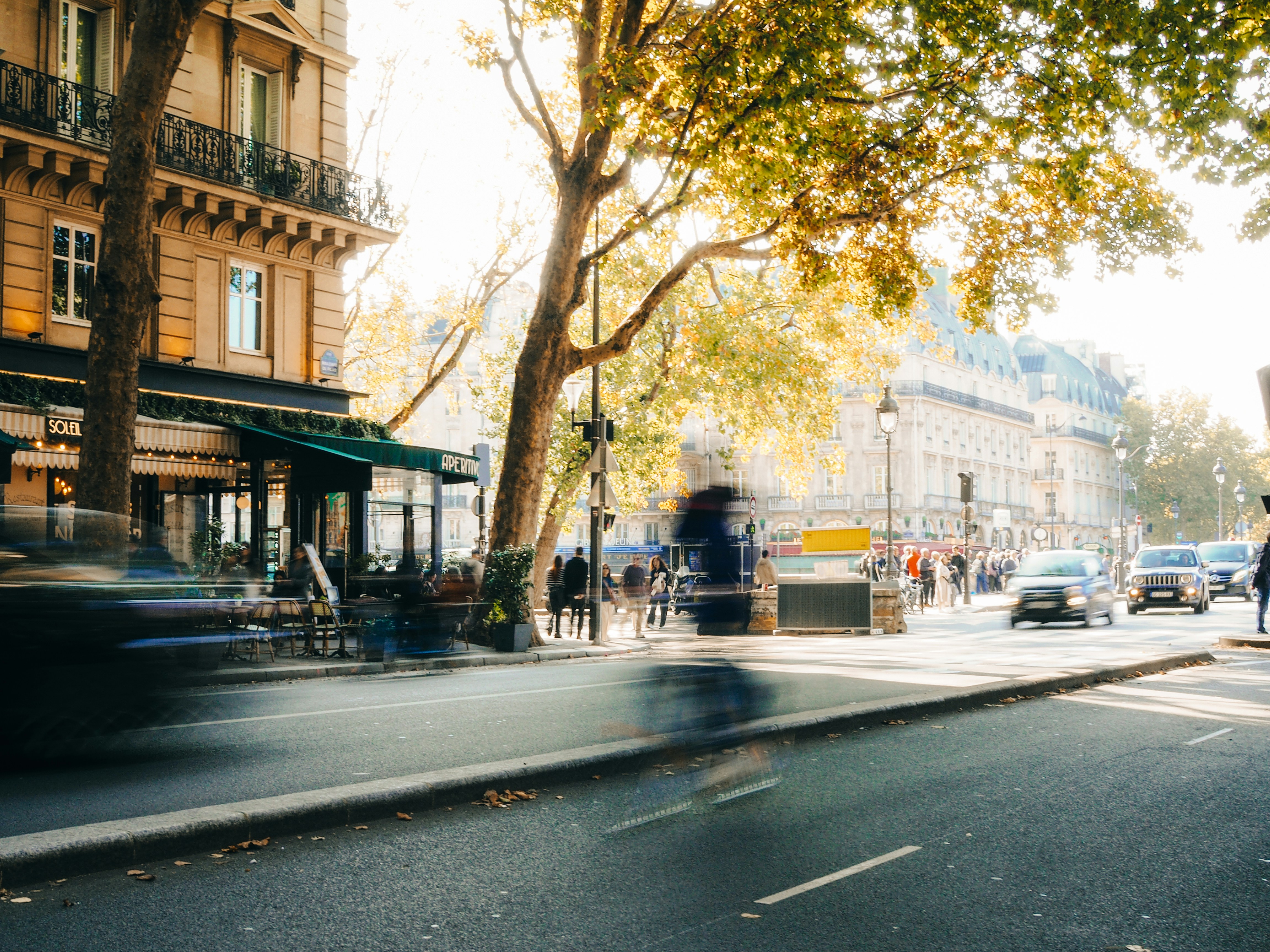 Paris glows beneath warm sunlight as elegant boulevards stretch through the heart of the city, creating a timeless scene of urban beauty and authentic street photography. Golden light reflects from historic facades, illuminating charming cafés, classic architecture, and bustling sidewalks filled with everyday life. The atmosphere feels effortlessly romantic, blending Parisian elegance with spontaneous street moments. Every corner offers visual storytelling, from stylish pedestrians and cozy terraces to iconic city perspectives. The scene captures wanderlust, culture, travel inspiration, and th