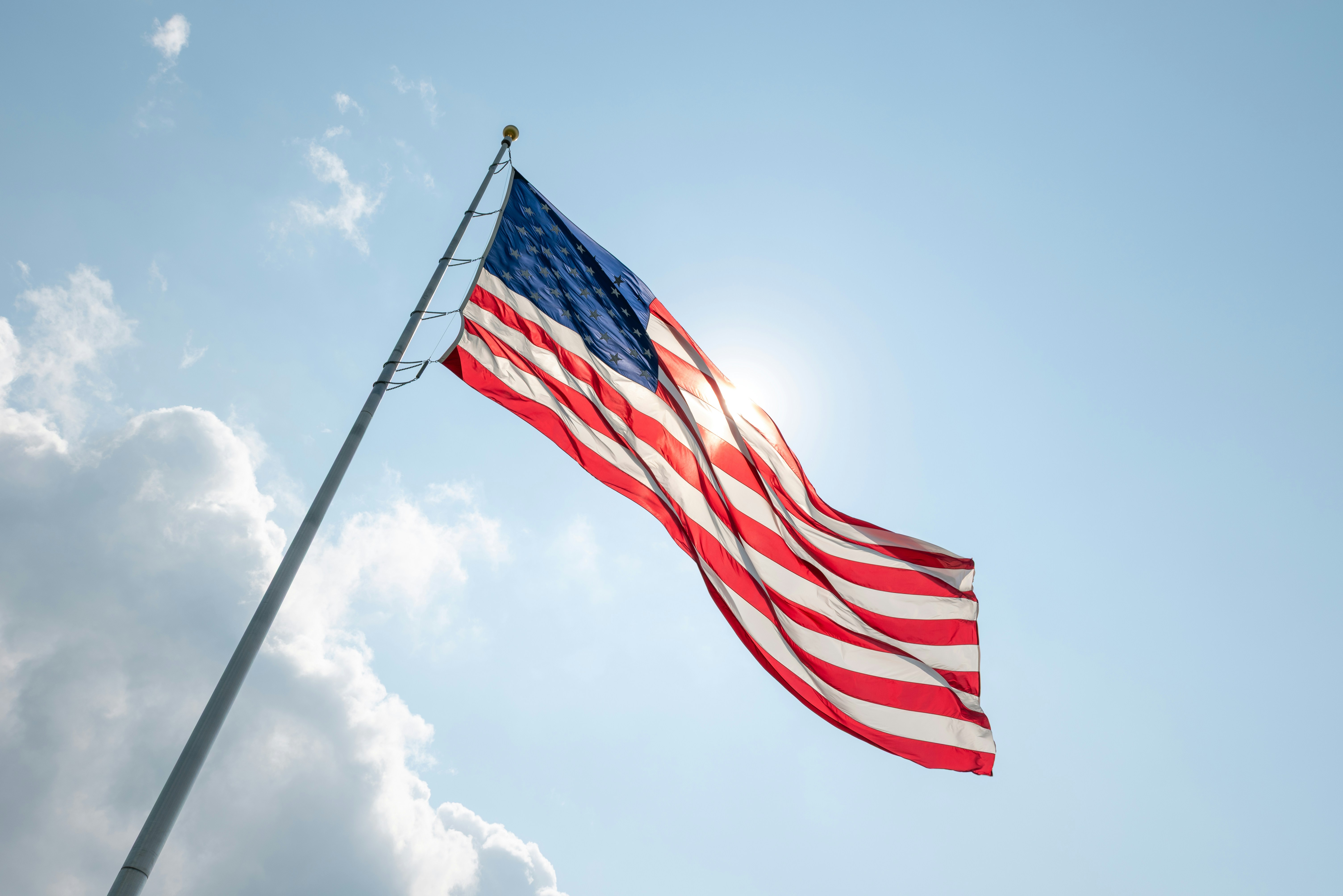 Flag in the Sun: A Gleaming Tricolor Above the Clouds