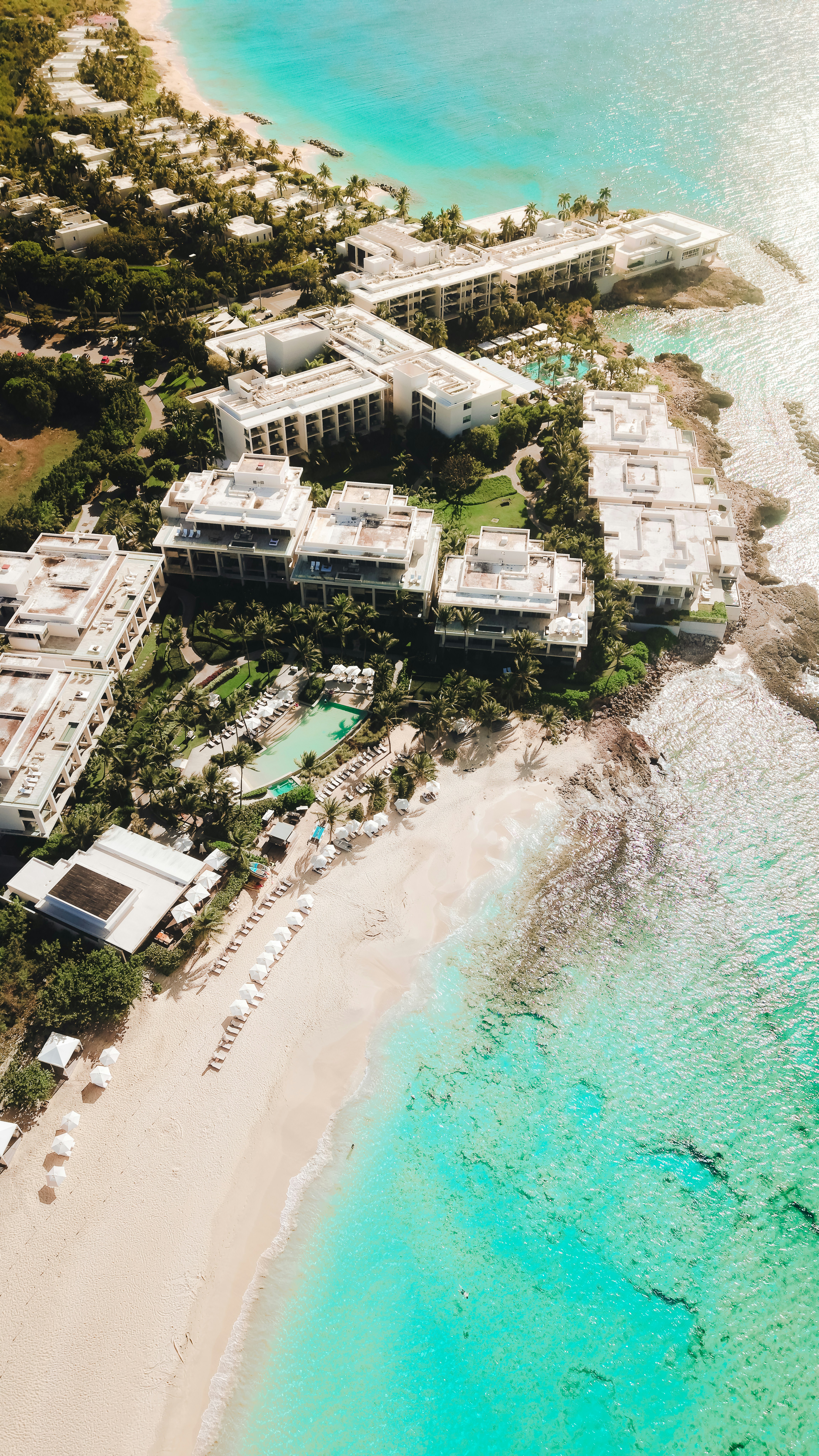 White resort blocks hug a turquoise shoreline from a birds-eye view