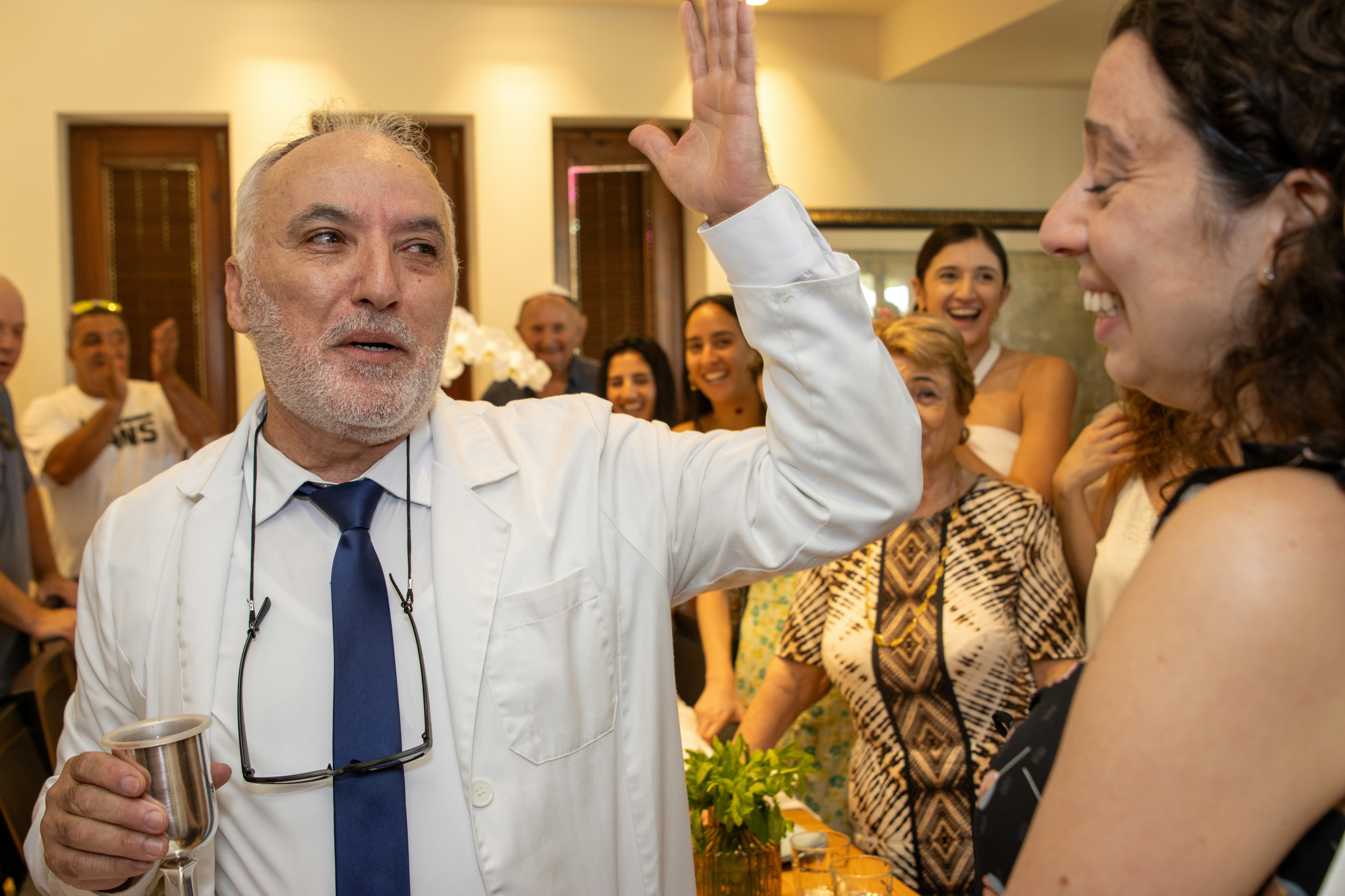 Bearded man raises hand while talking to a smiling woman.