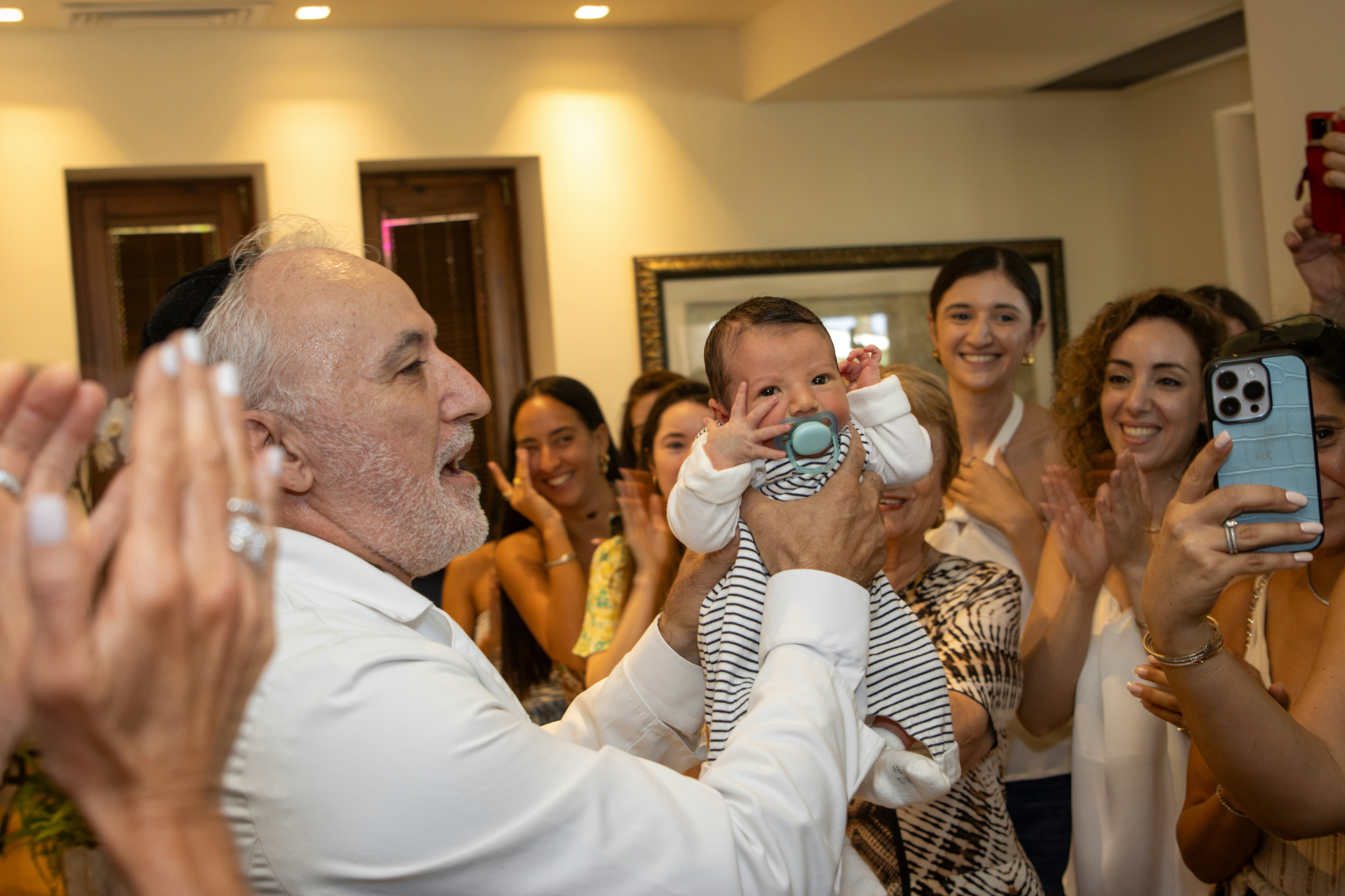 Family Celebration: A Grandfather Lifts a Baby Amid Cheerful Guests