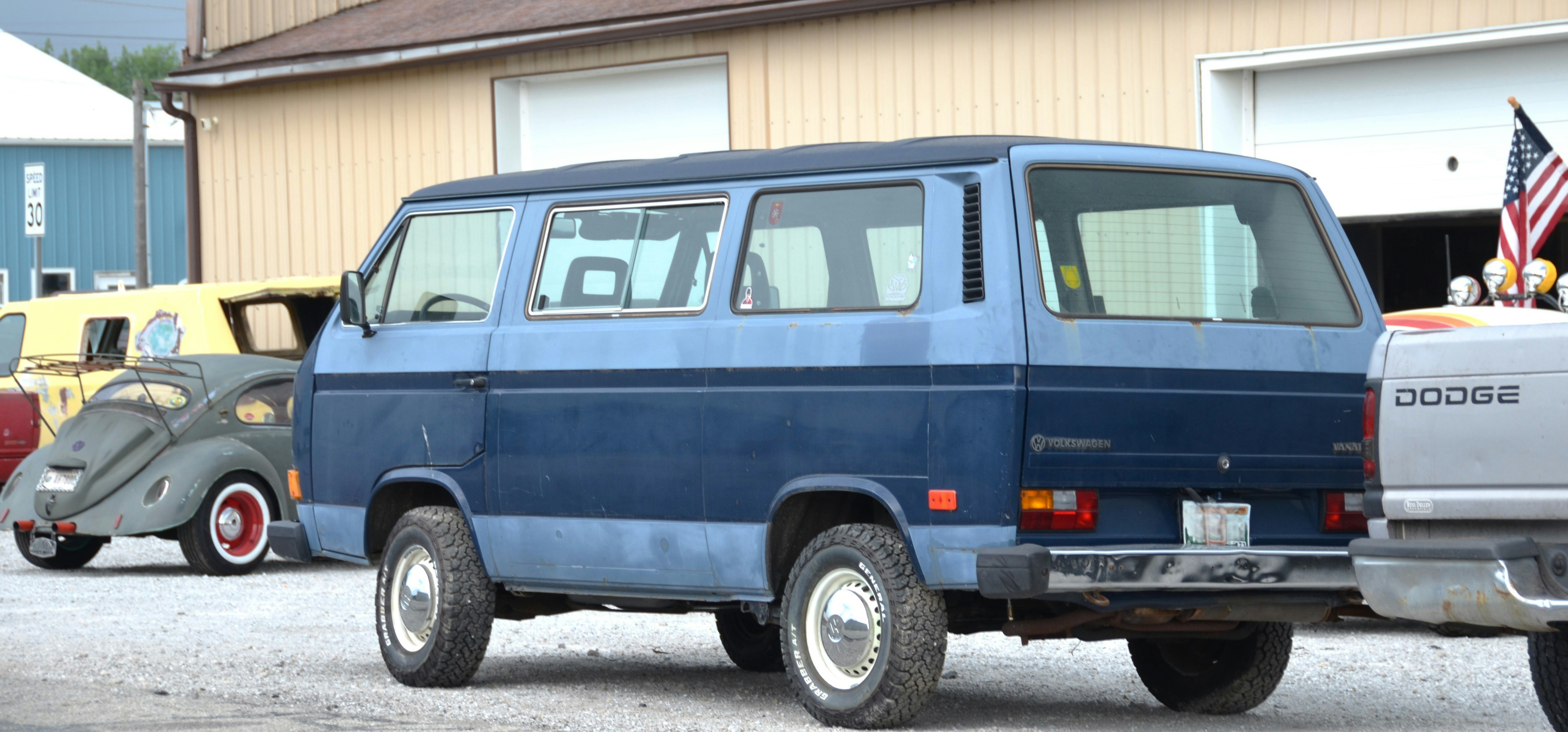 Blue vintage van among a row of classic cars at a dusty lot