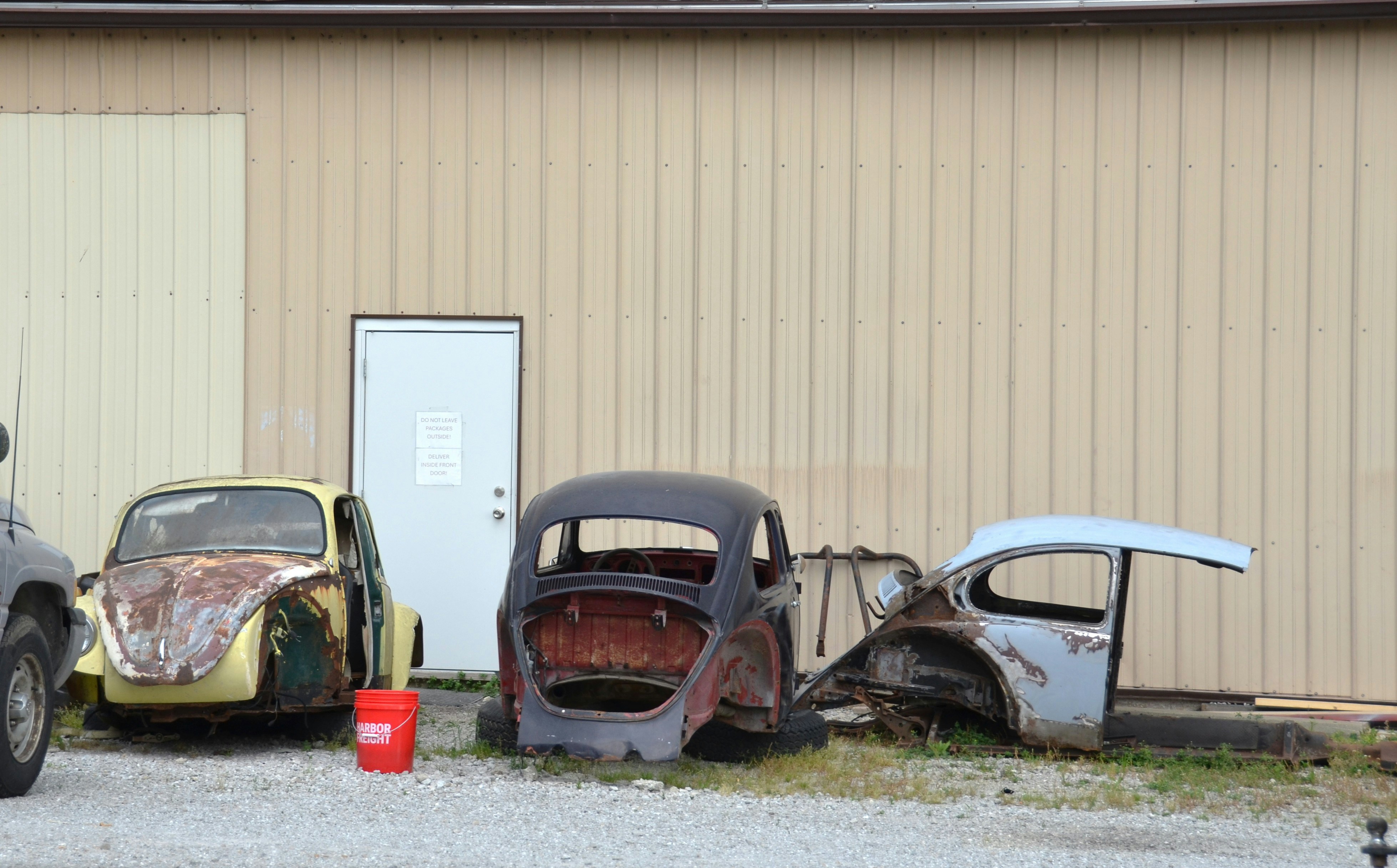Rusting Remnants: Abandoned Car Bodies Line a Dismal Warehouse