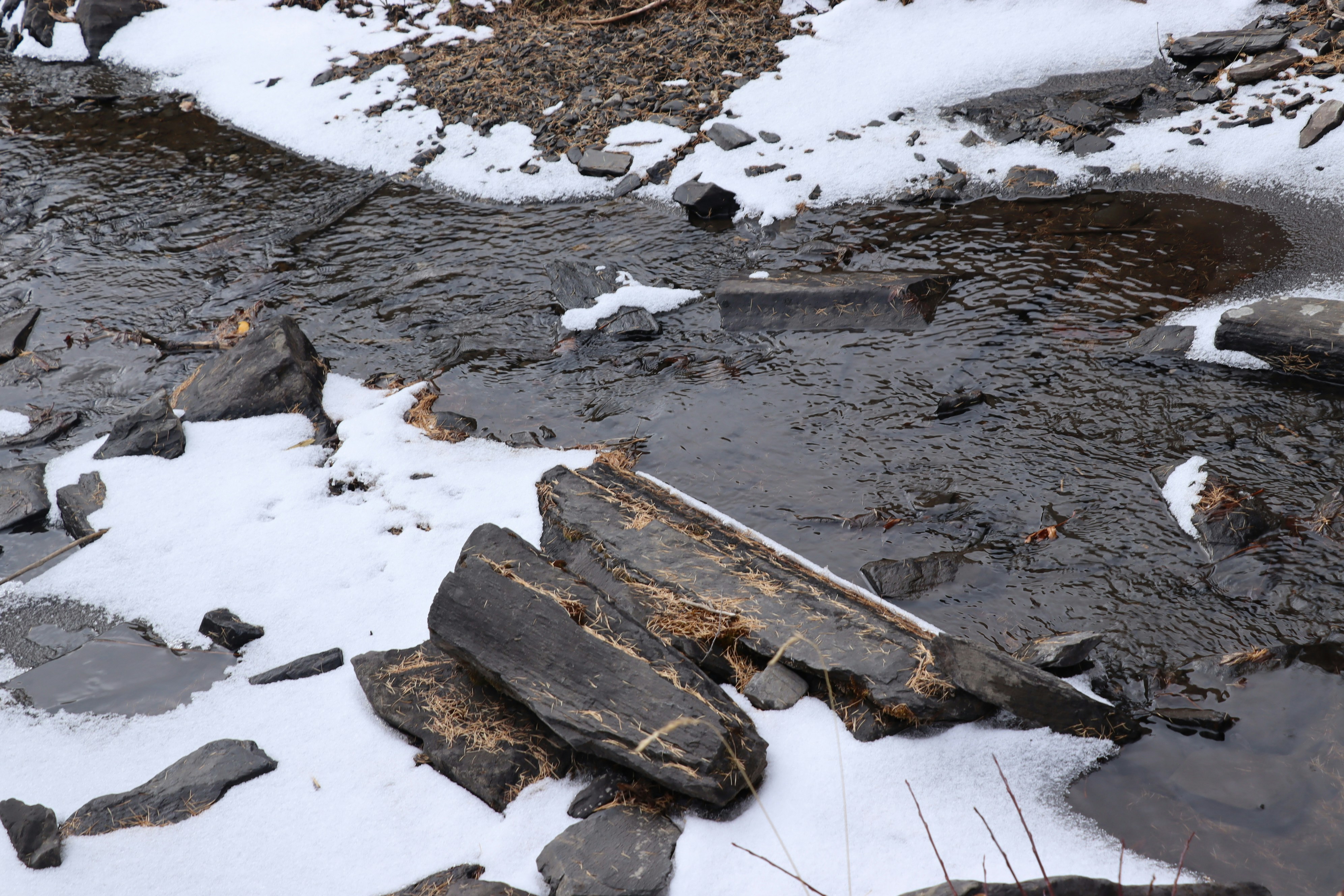 Rugged Stones and Melting Snow Slip Through a Narrow Stream