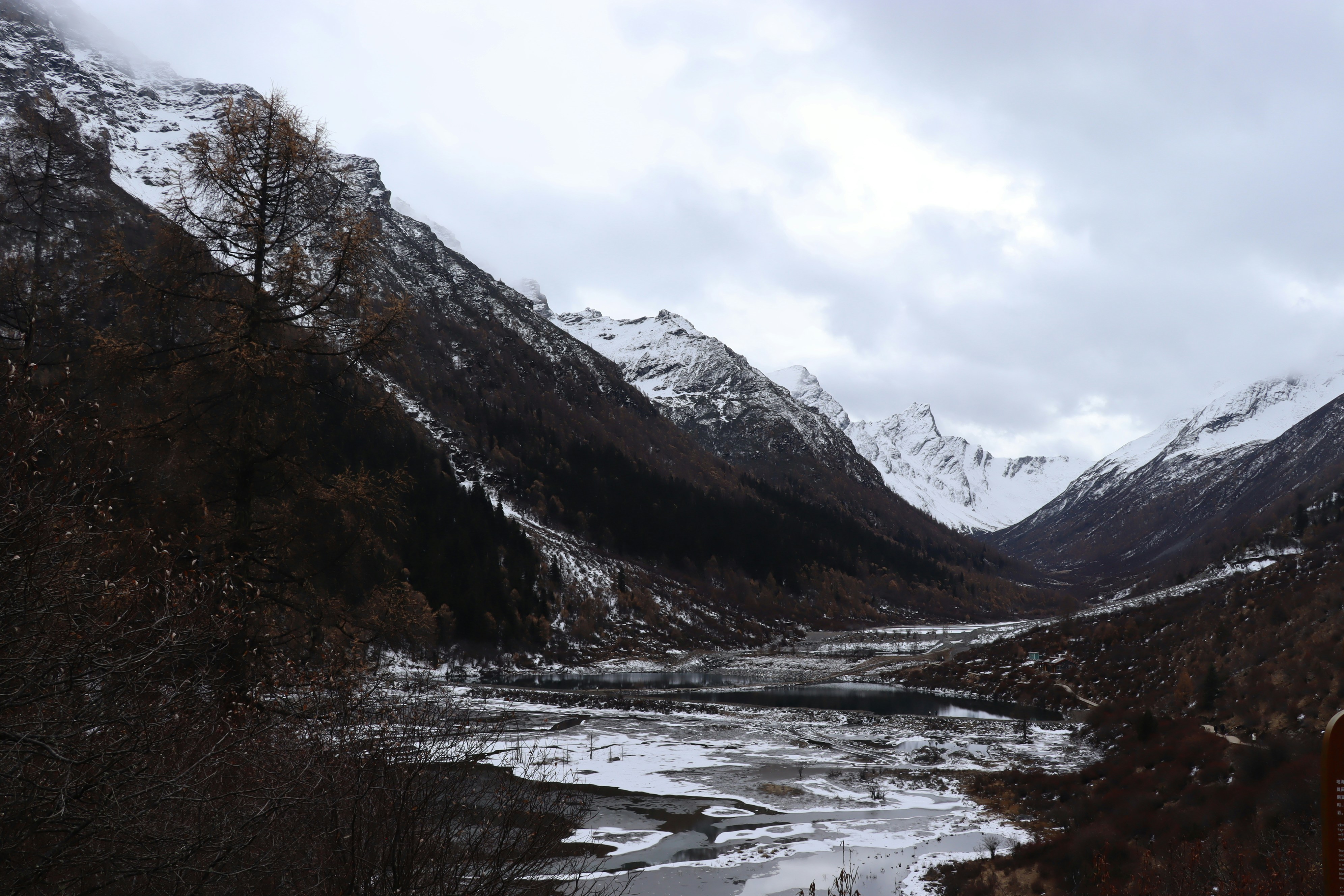 Snow-covered valley with a river winding through mountains.