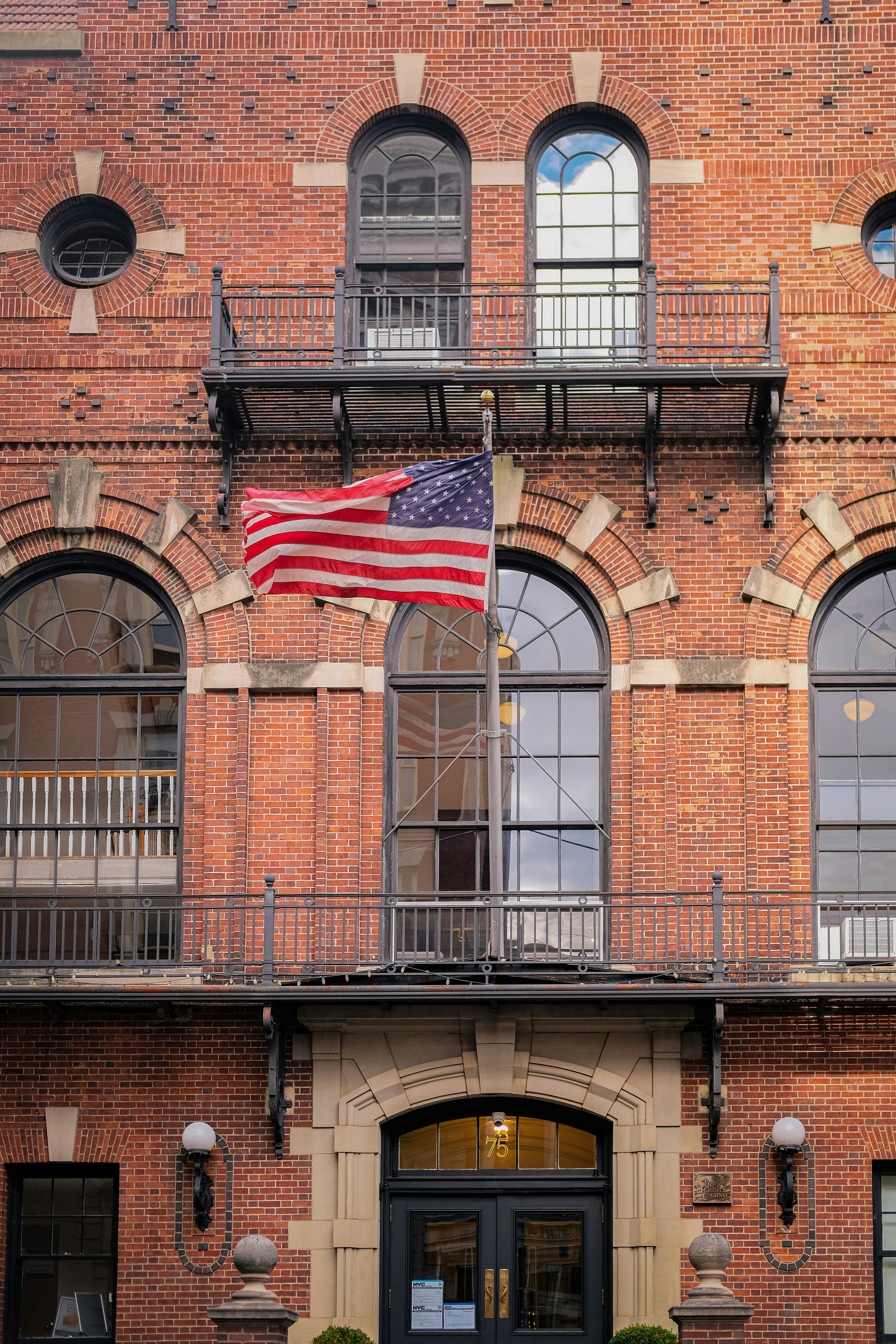 American Flag over a Brick Facade: Hotel Window Balcony Portrait