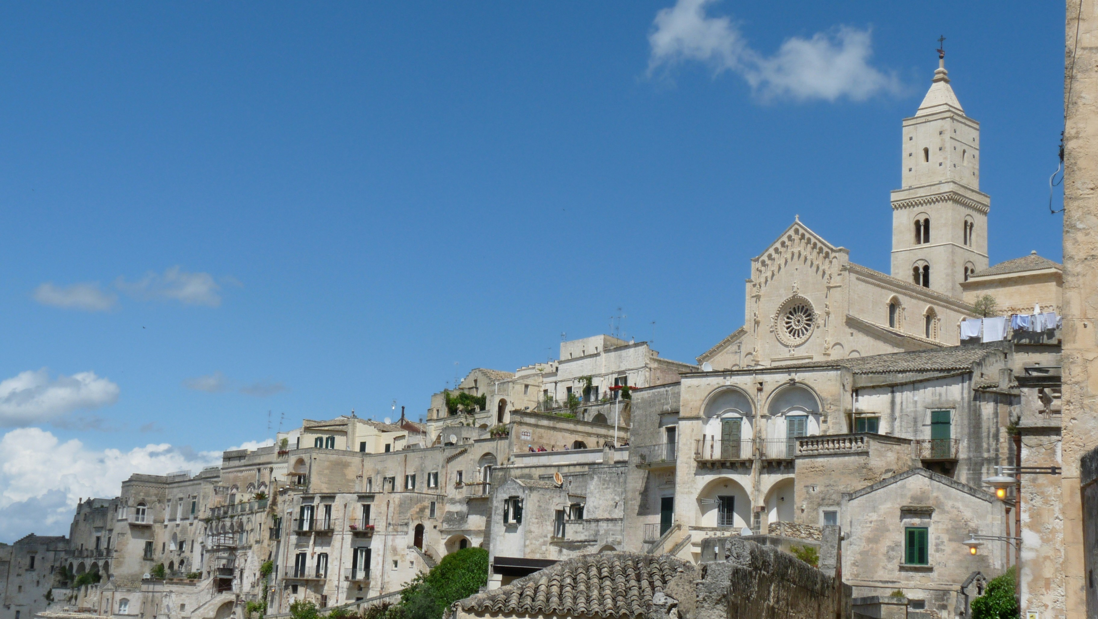 Stone Skyline: A Tuscan-Catholic Village Rises under a Clear Blue Dome