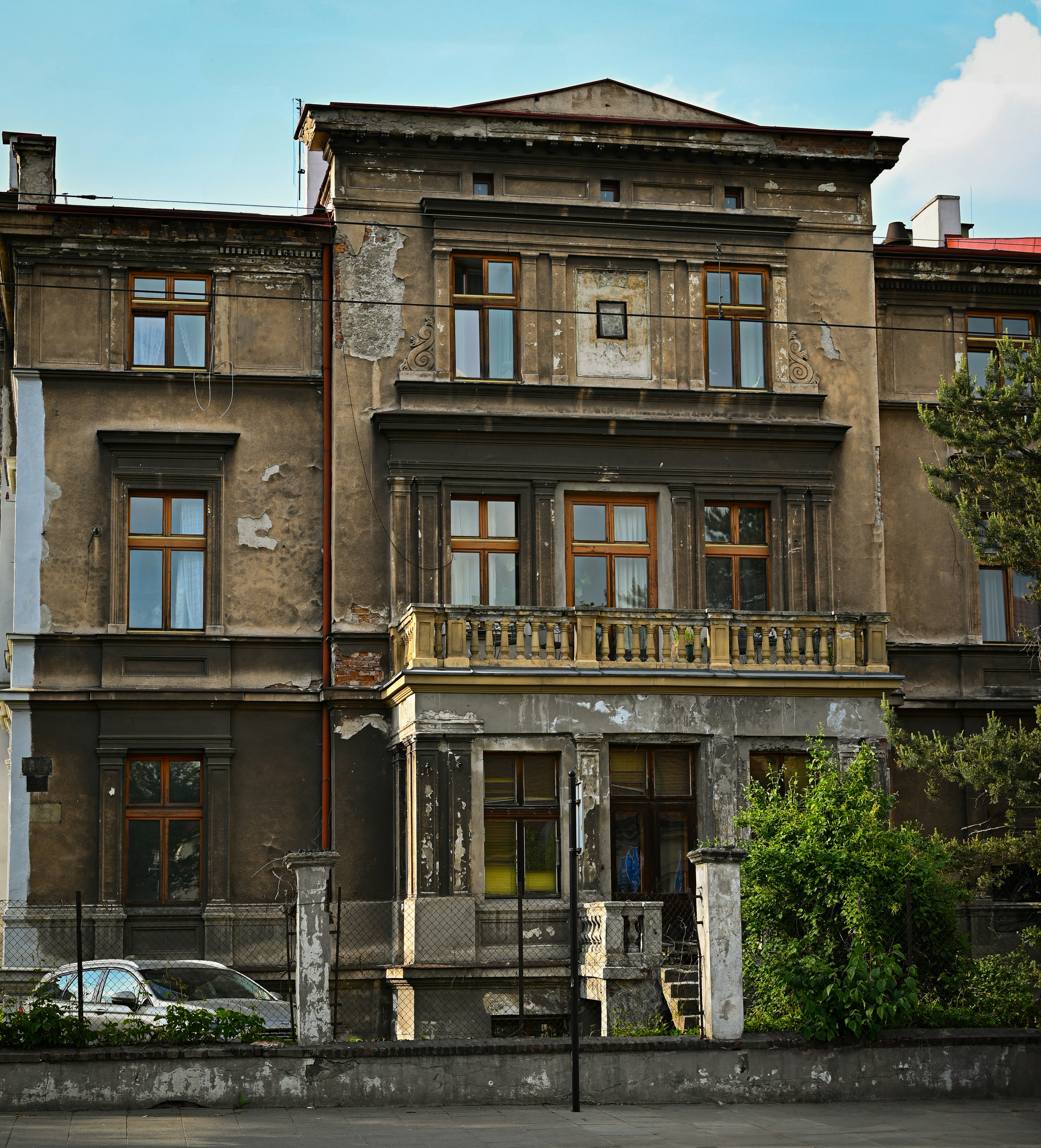 Weathered historic building facade with peeling plaster and wooden windows in Kraków, Poland.
