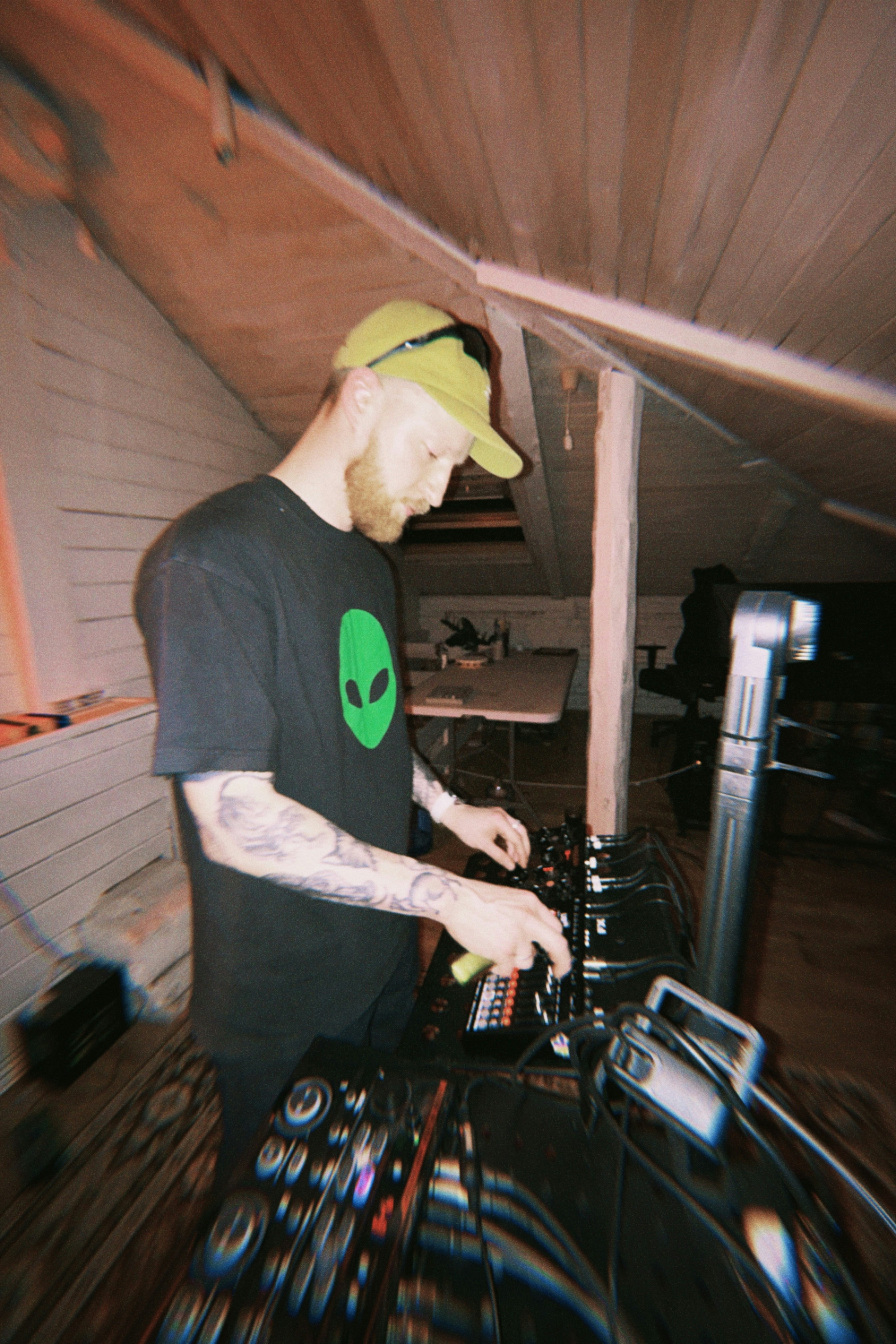 Man in alien t-shirt operating dj equipment.