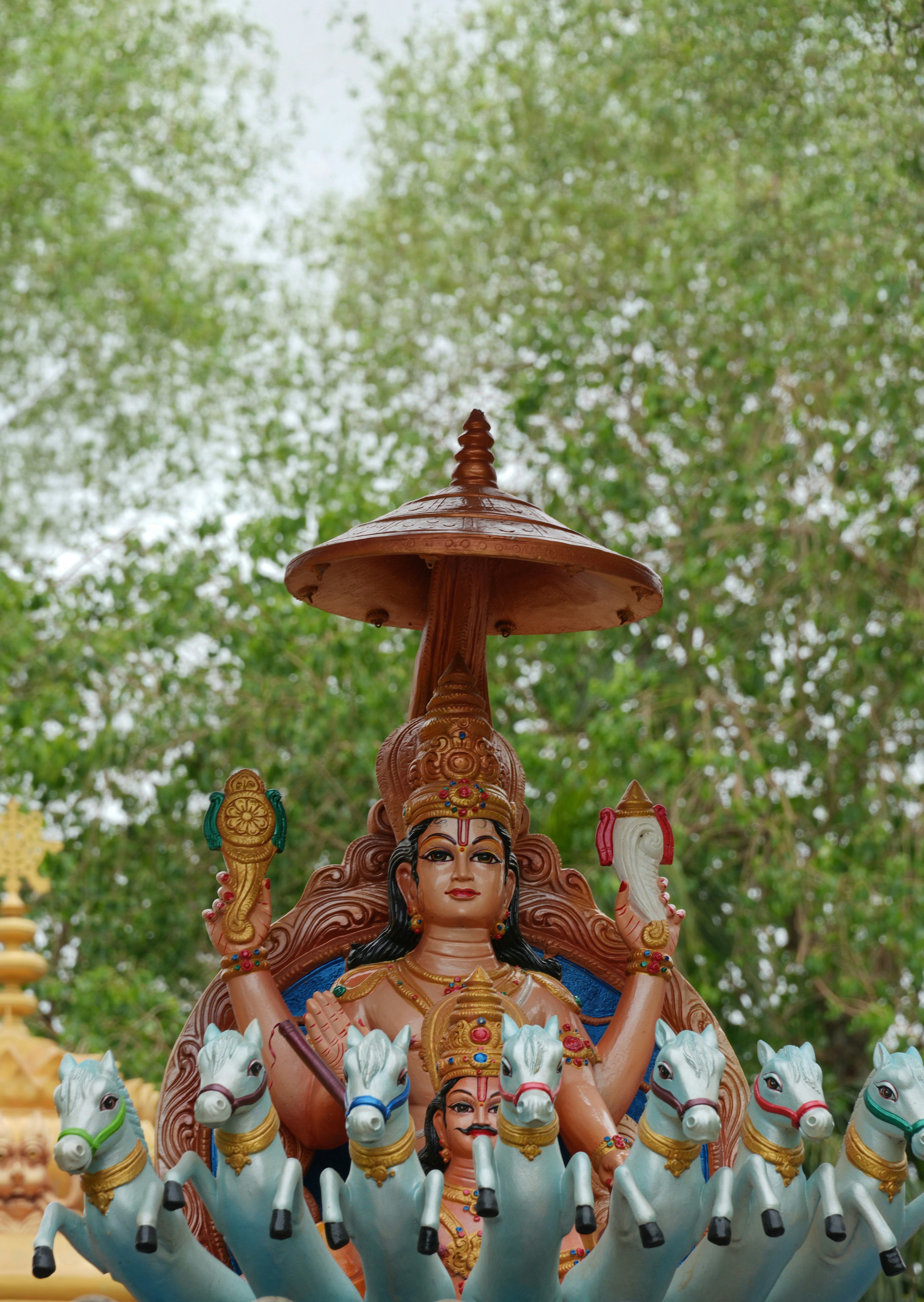 Colorful statue of a hindu deity on a horse-drawn chariot.