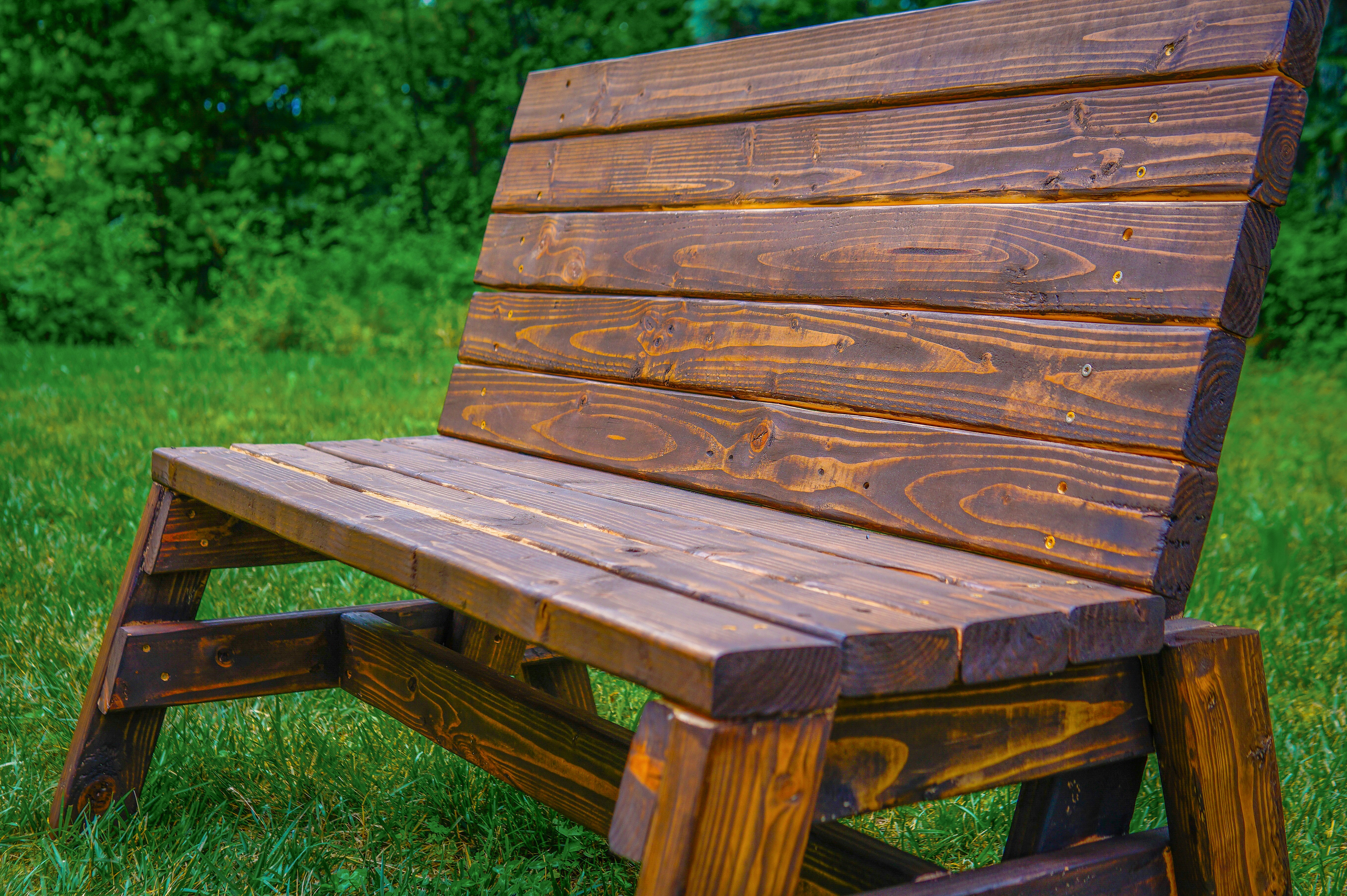 Sunlit Wooden Bench Reclining into a Lush Green Clearing
