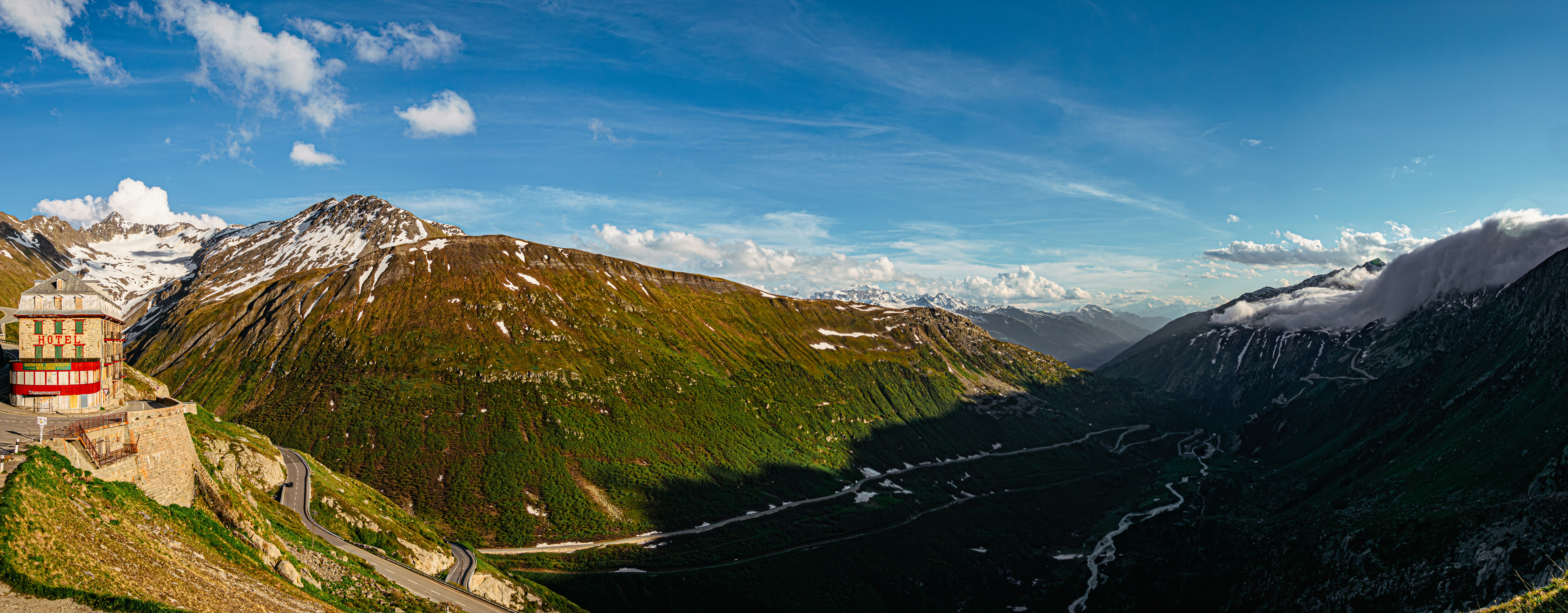 Majestic mountain panorama with a building, valley, and snowy peaks.
