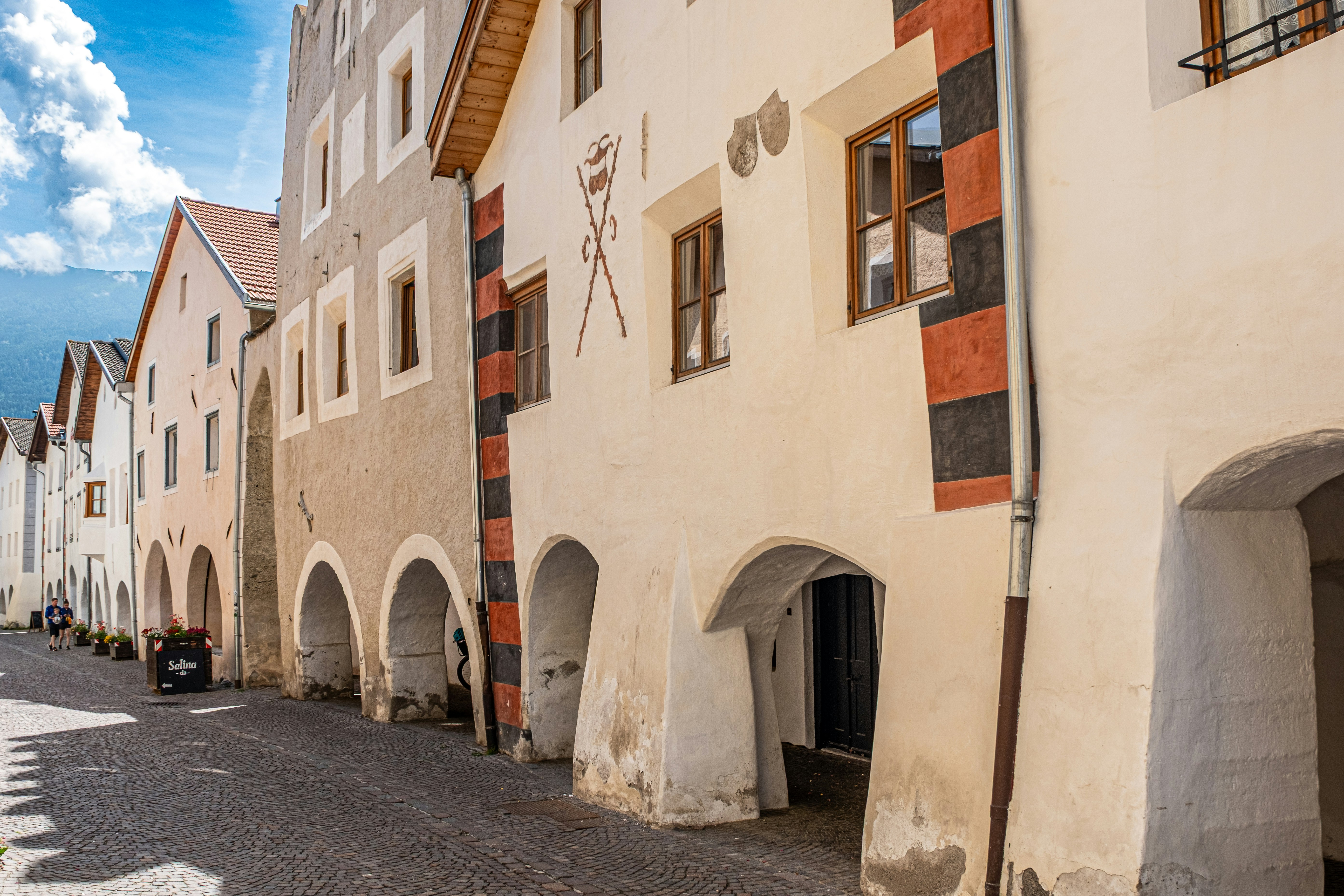 Quaint Alpine Facades: A Sunlit Street of Arched Alleys
