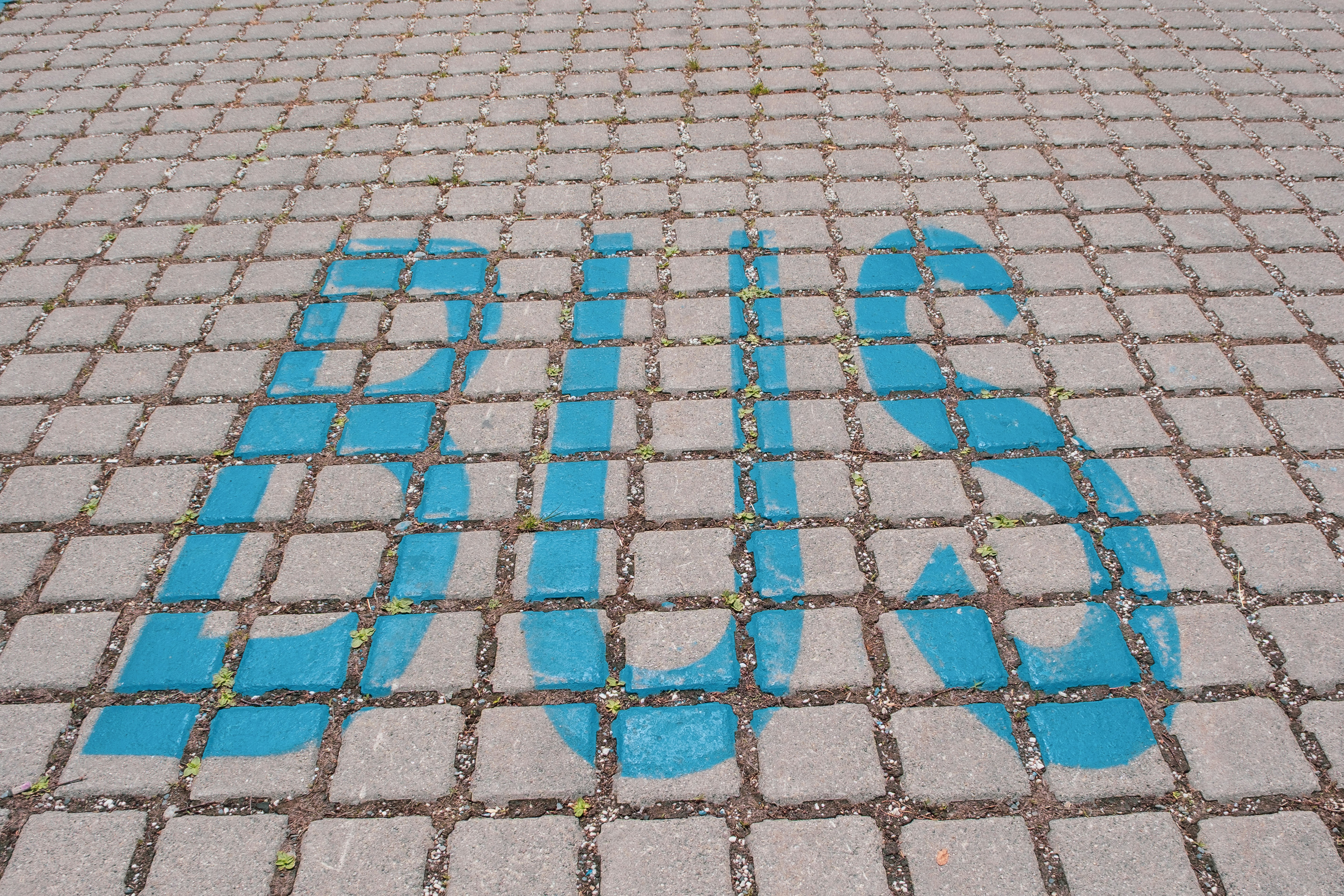 Blue Letters on Cobblestone Path: A Quiet Street Moment