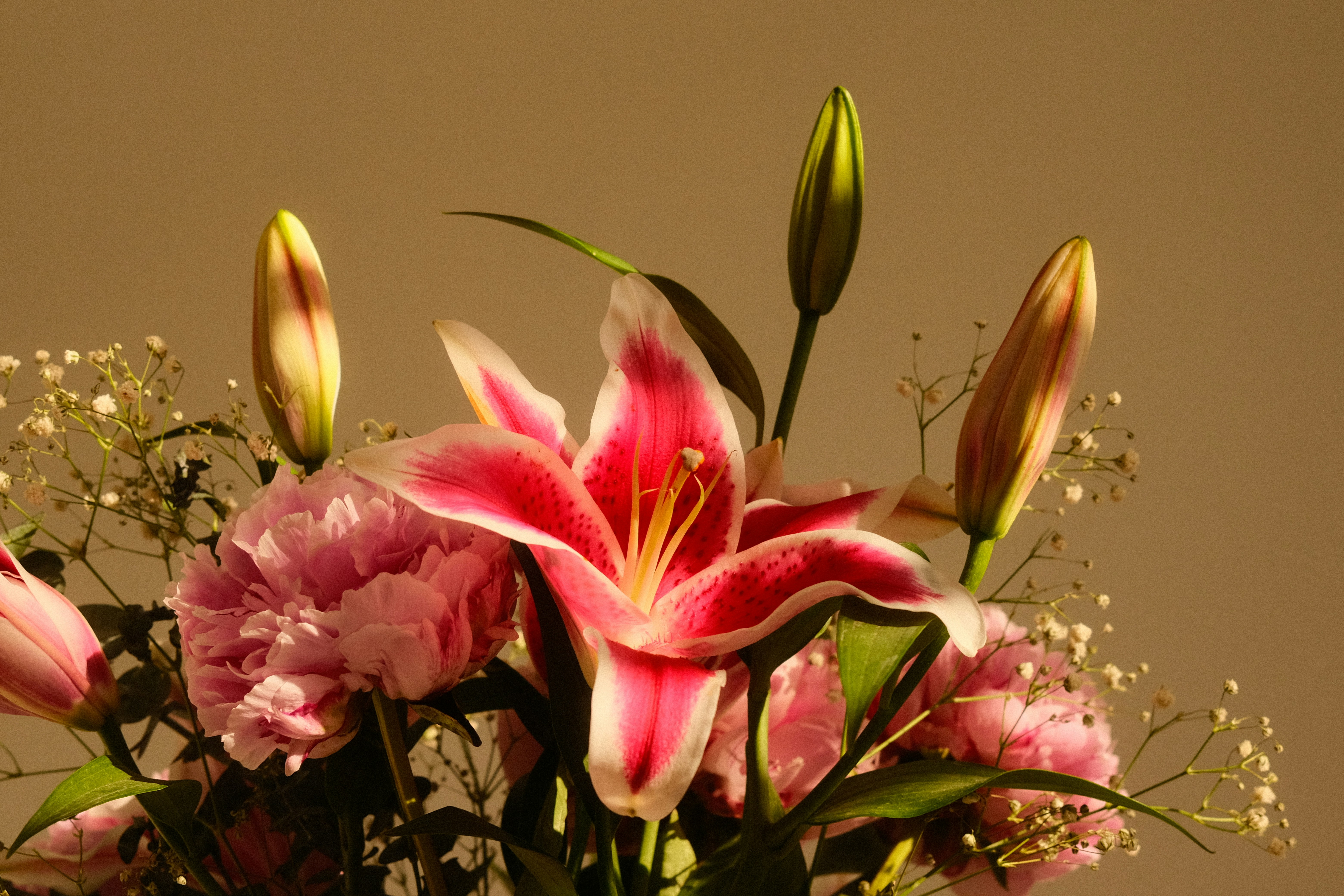 Vibrant pink lily, carnations, and buds in a floral bouquet.