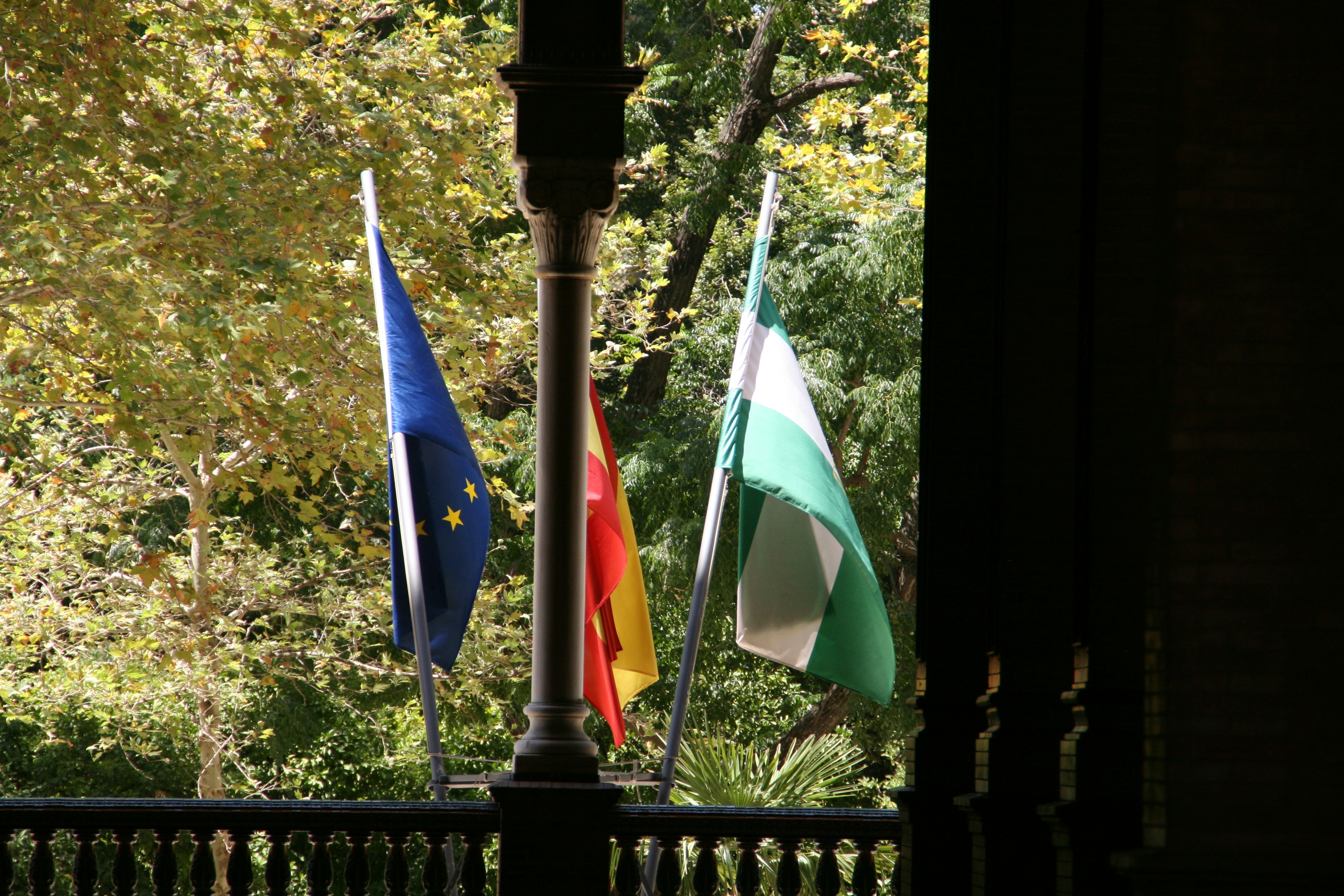 Flags in a shaded balcony frame against leafy backdrop