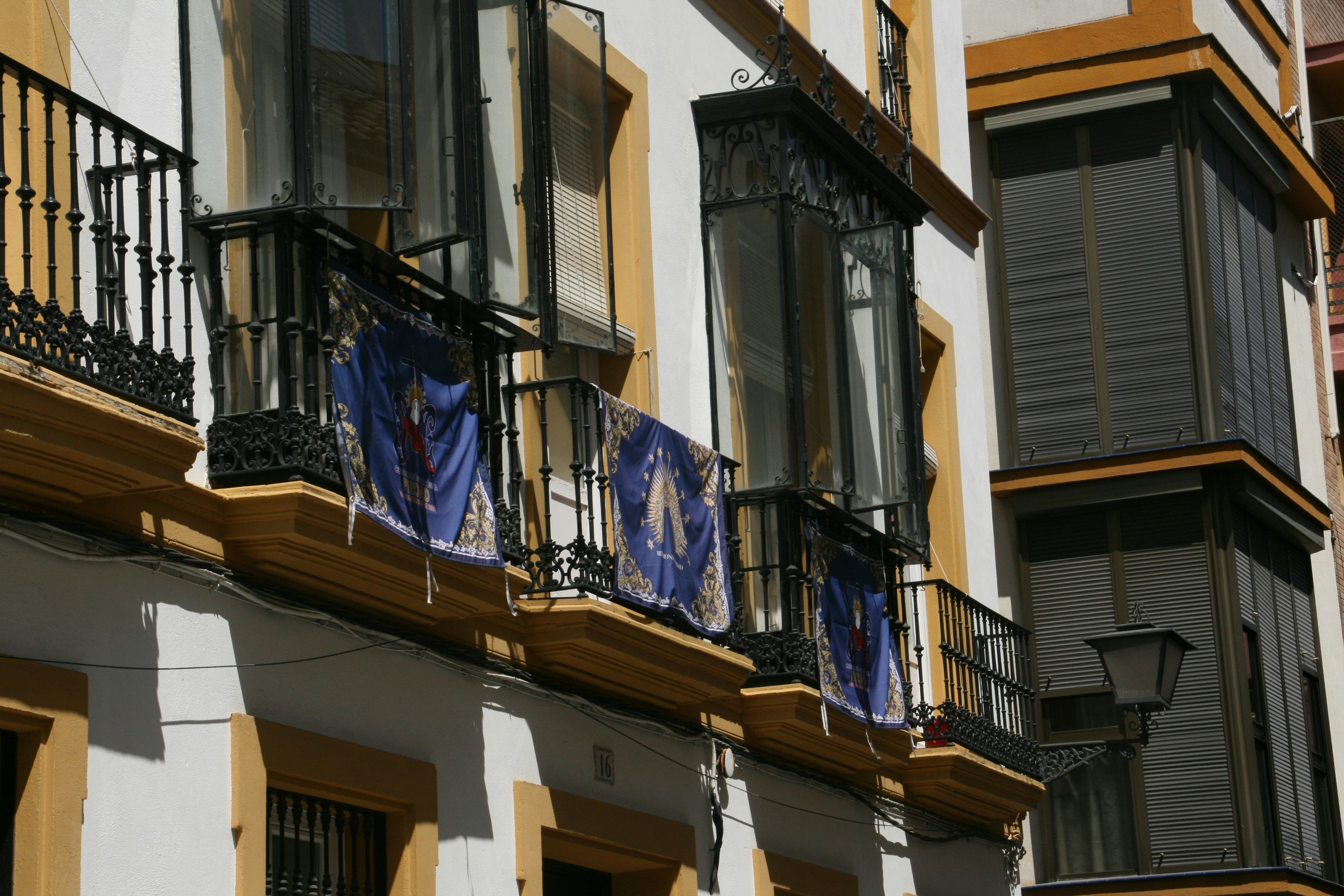 Balcony Threads: Flags Cling to the Sunlit Facade