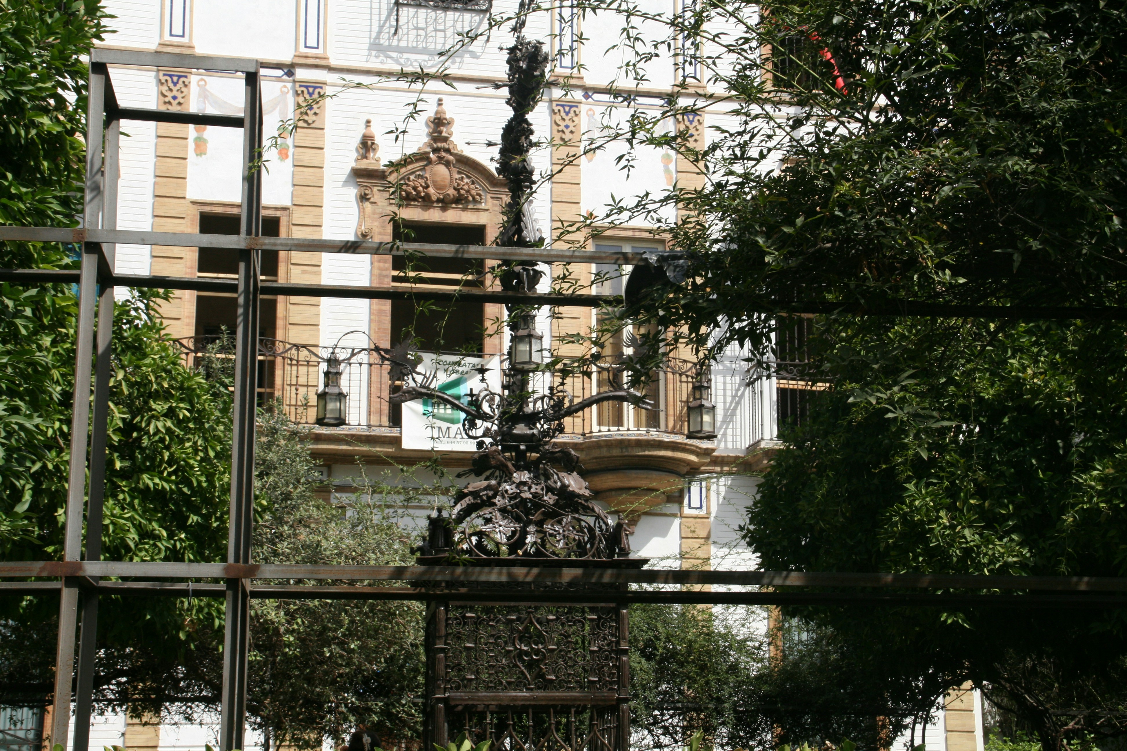 Ornate gate and historic facade peeking through tree canopy