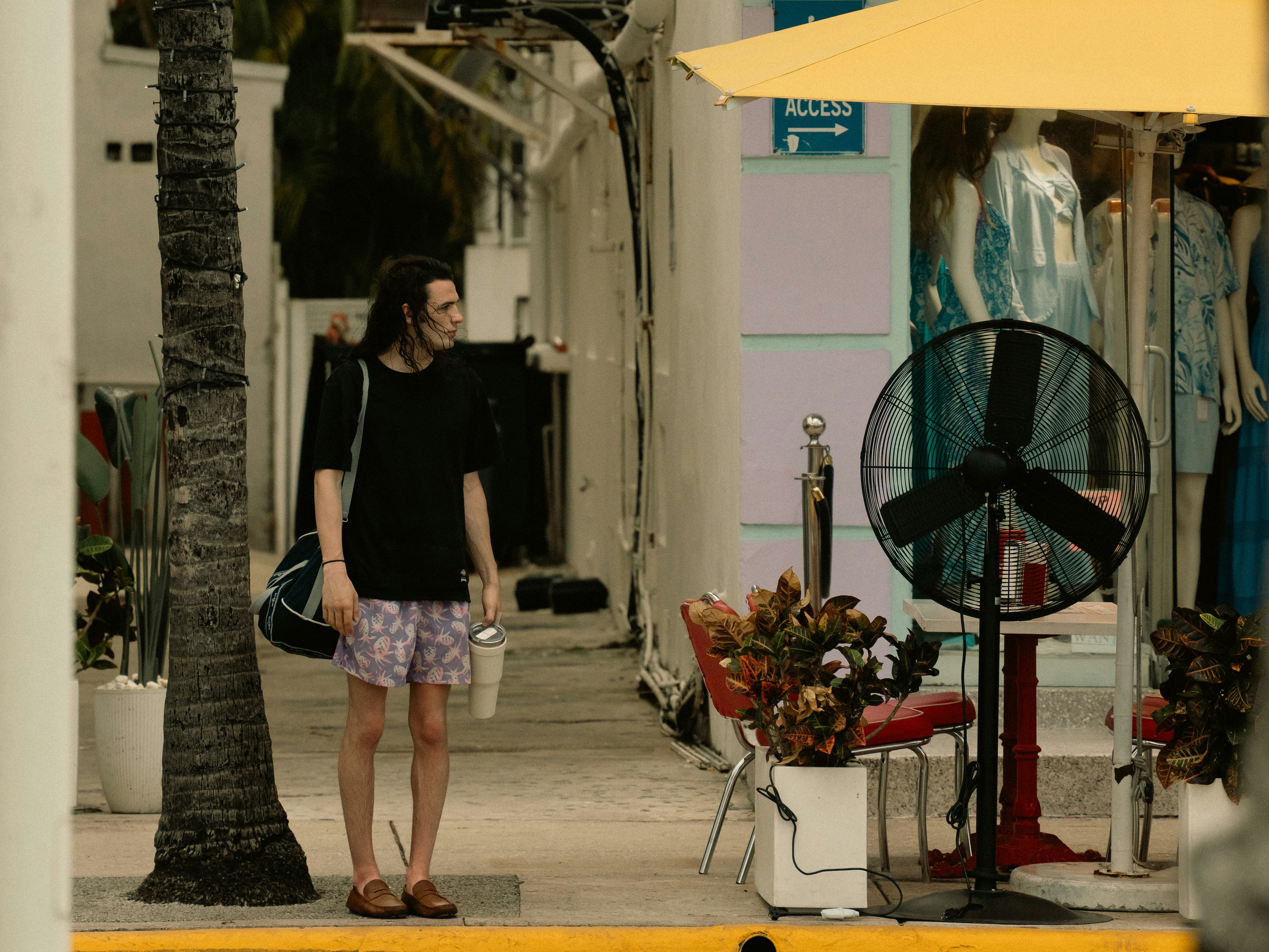 Street-side Pause: A Young Man Seeks Shade and a Drink