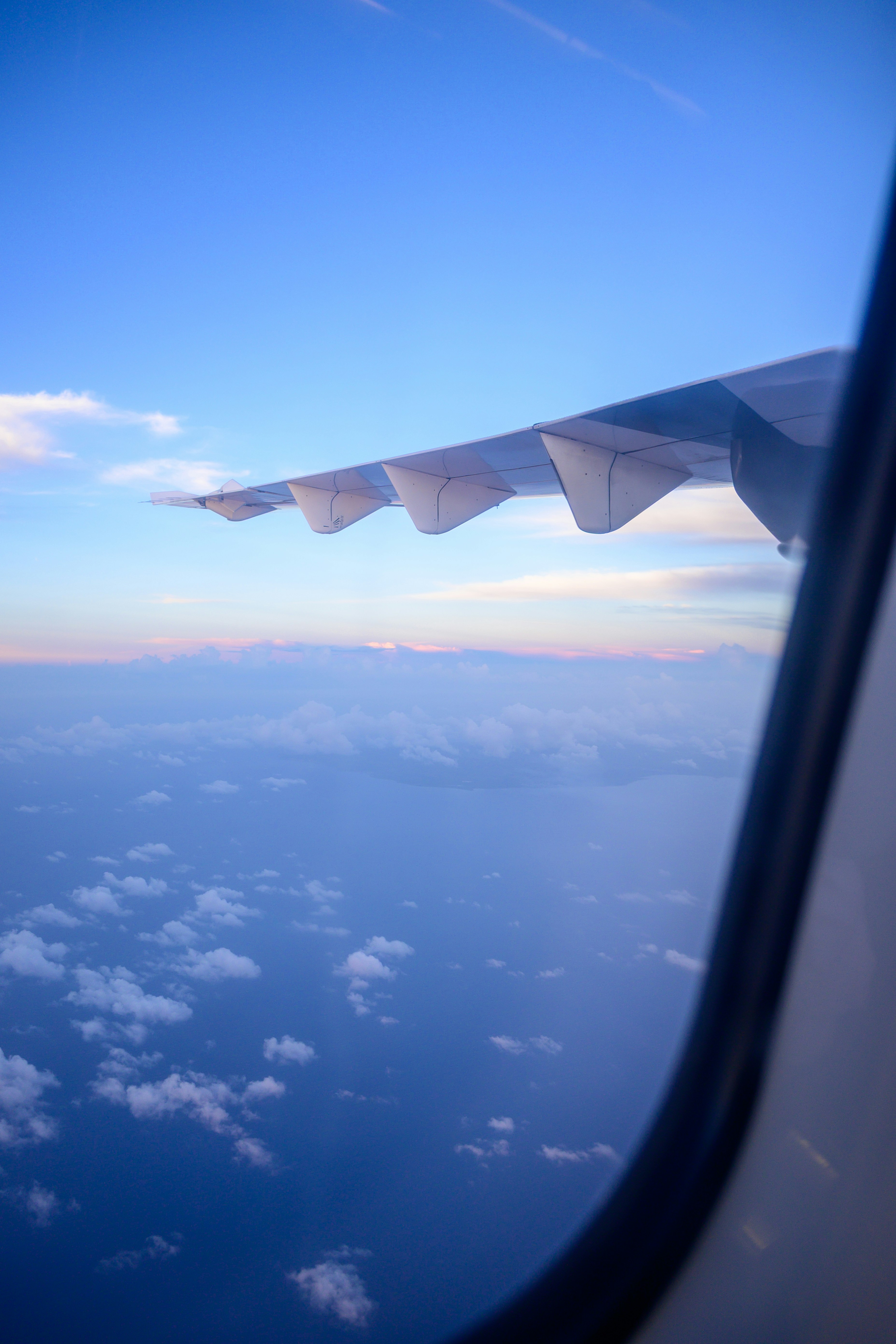 Skyline of clouds beneath a distant wingtip at sunset