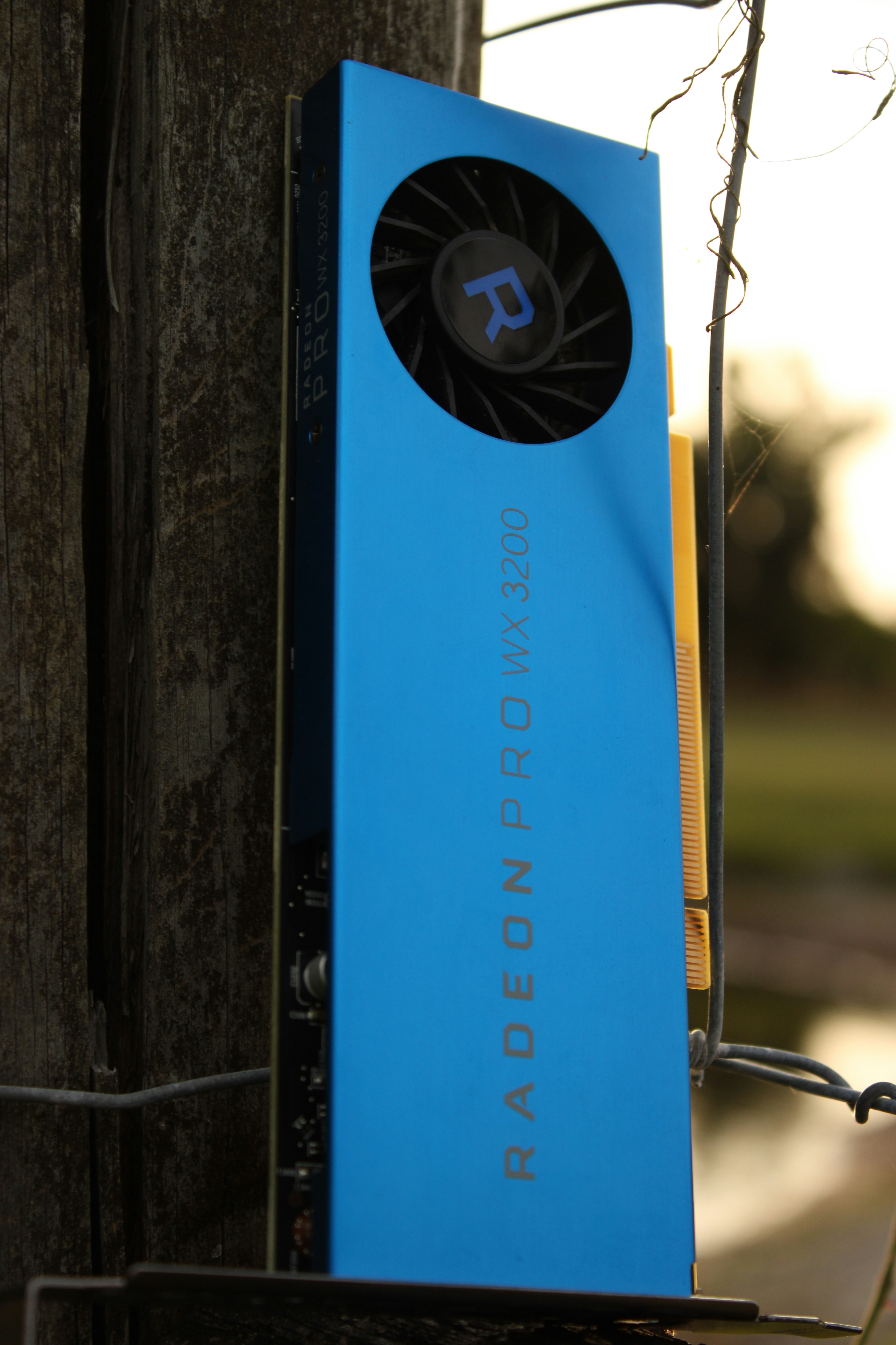 Blue Radeon RX Card Beside a Weathered Post by a Quiet Stream