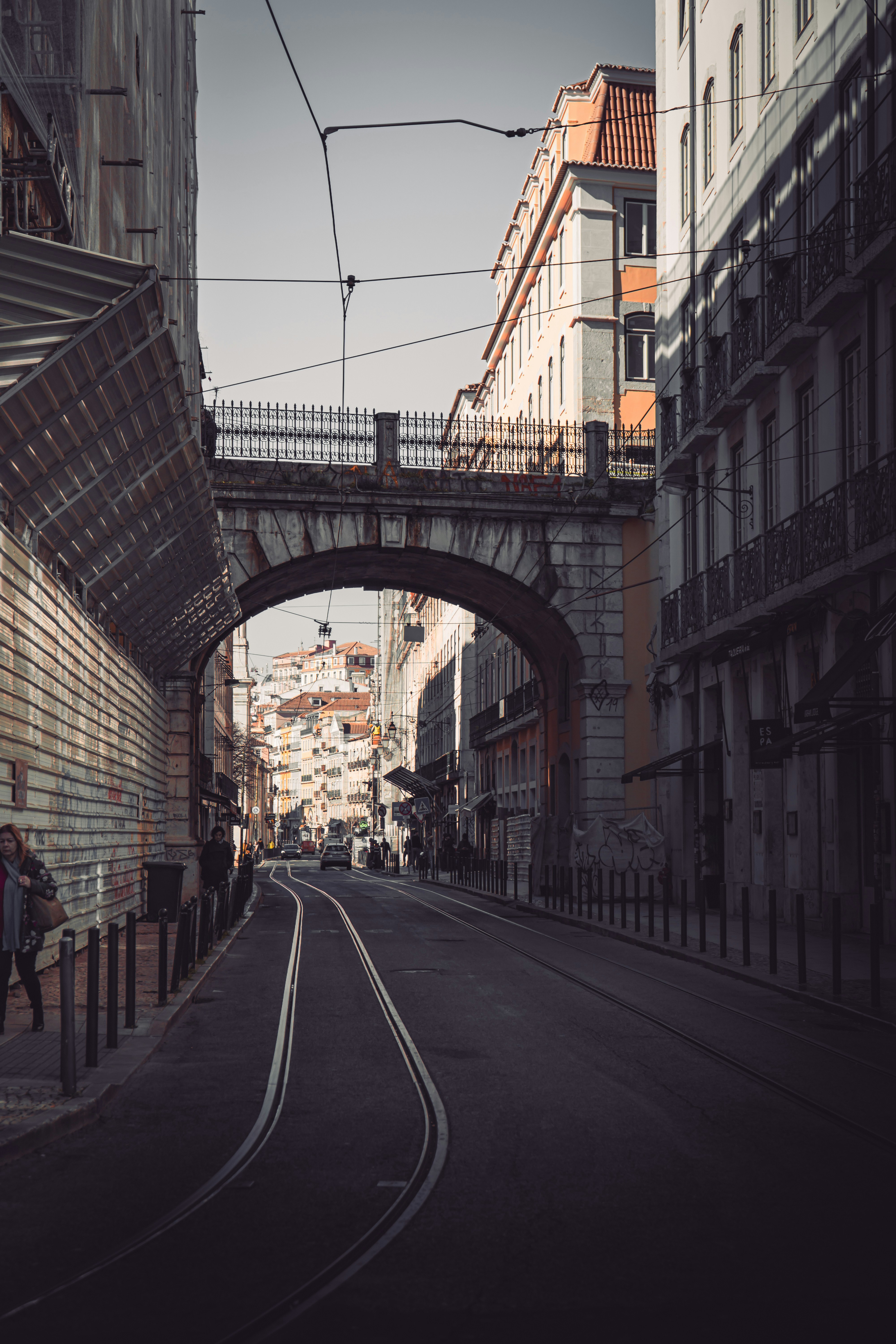 Archway Over Lane: Tram Tracks Lead Toward a Sunlit Street