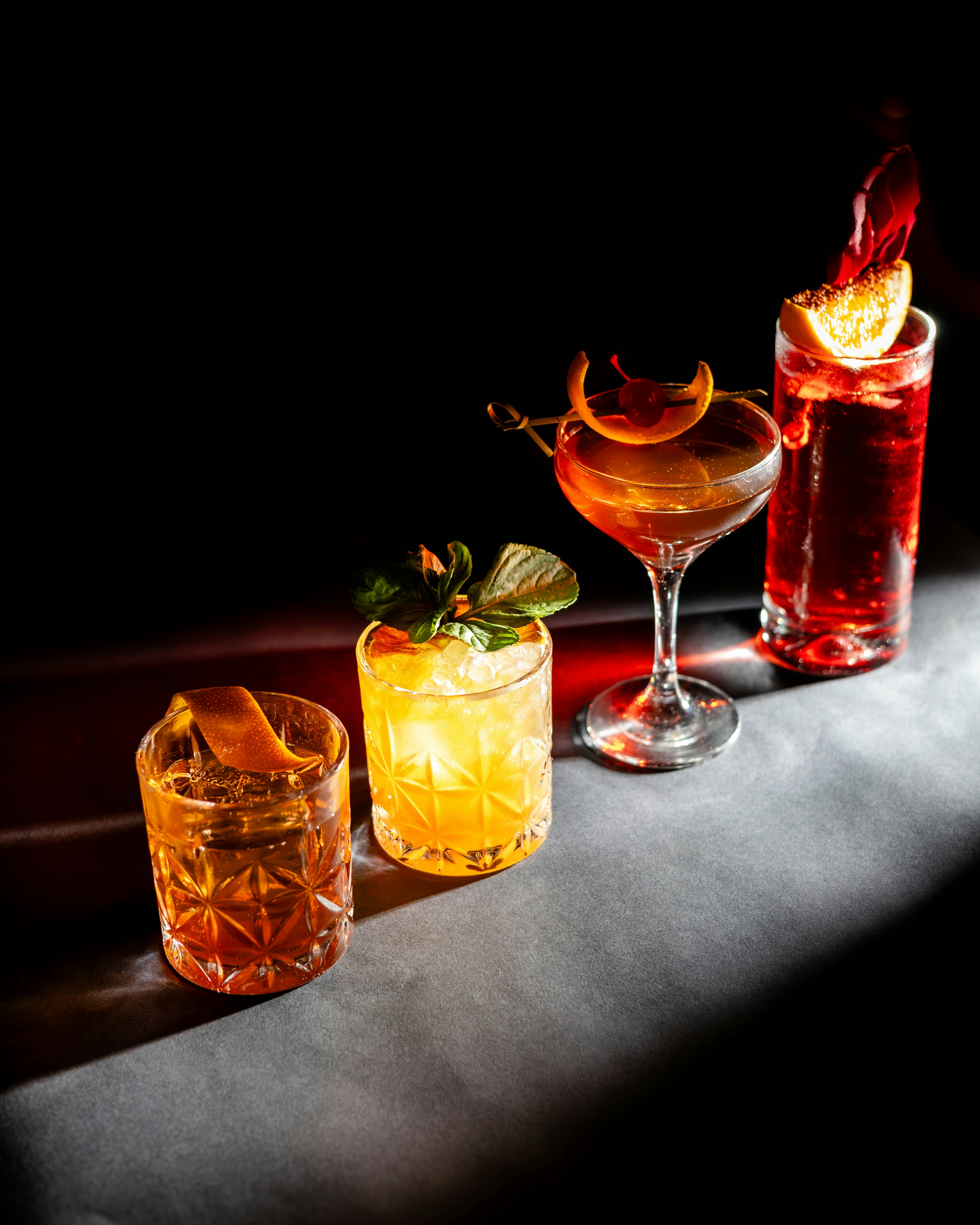 A quartet of luminous cocktails marching along a neon-dark runway