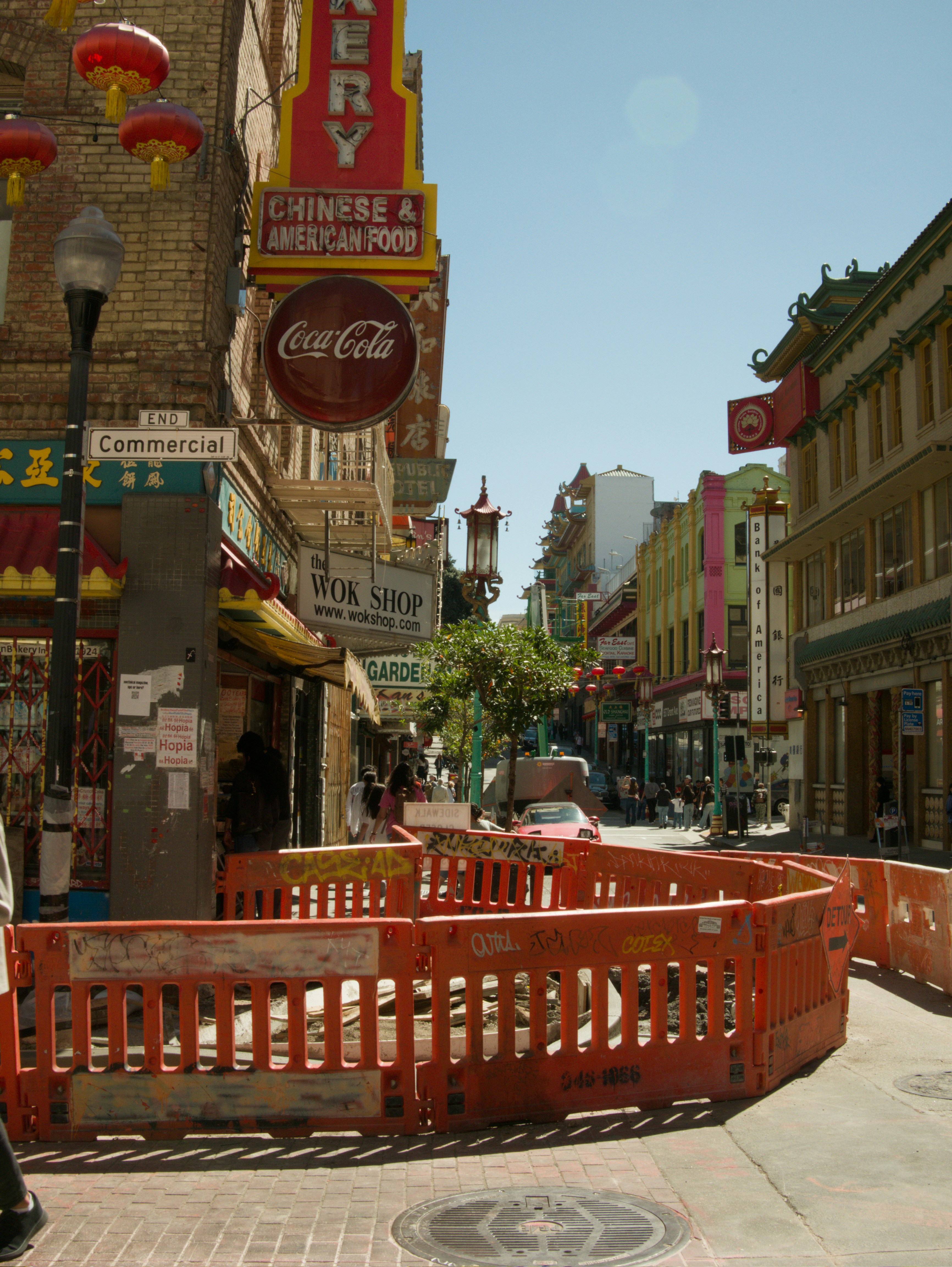 Sunlit Chinatown Street Scene Beside Orange Barrier Fences