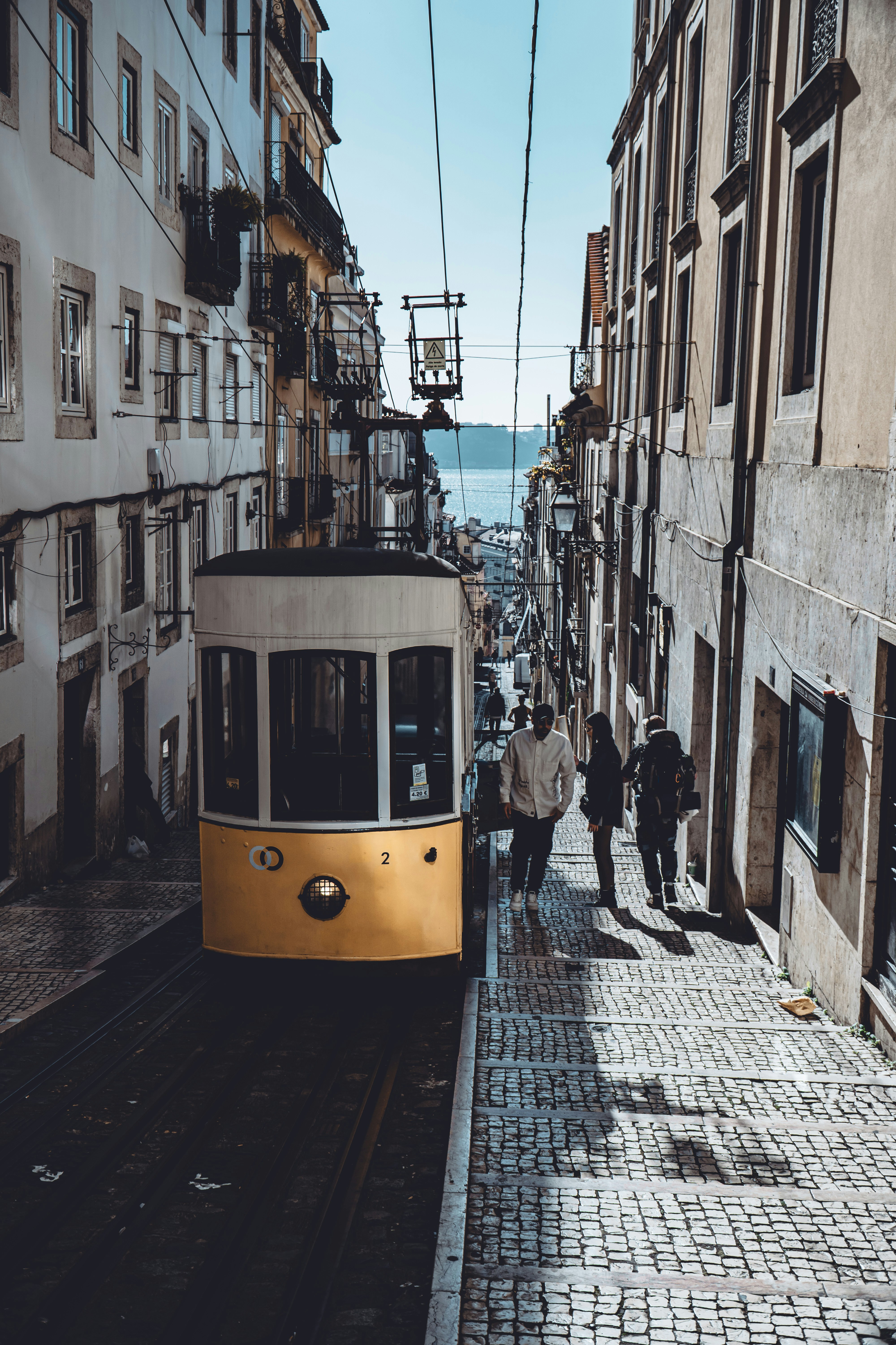 Yellow tram carving a path through sunlit Rua da Lisboa