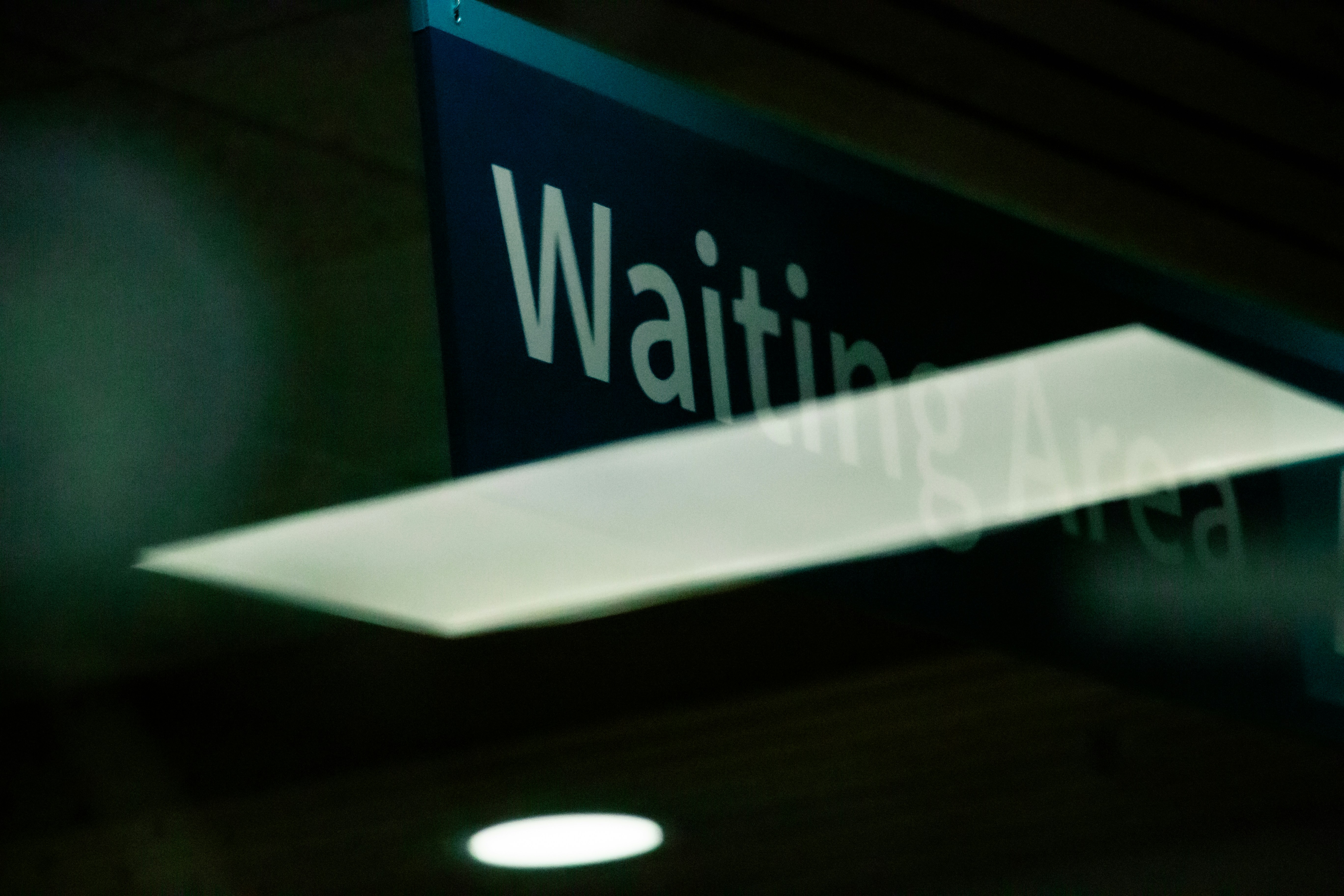 Blurred Waiting Area Sign Slants Through a Dim Subway Corridor
