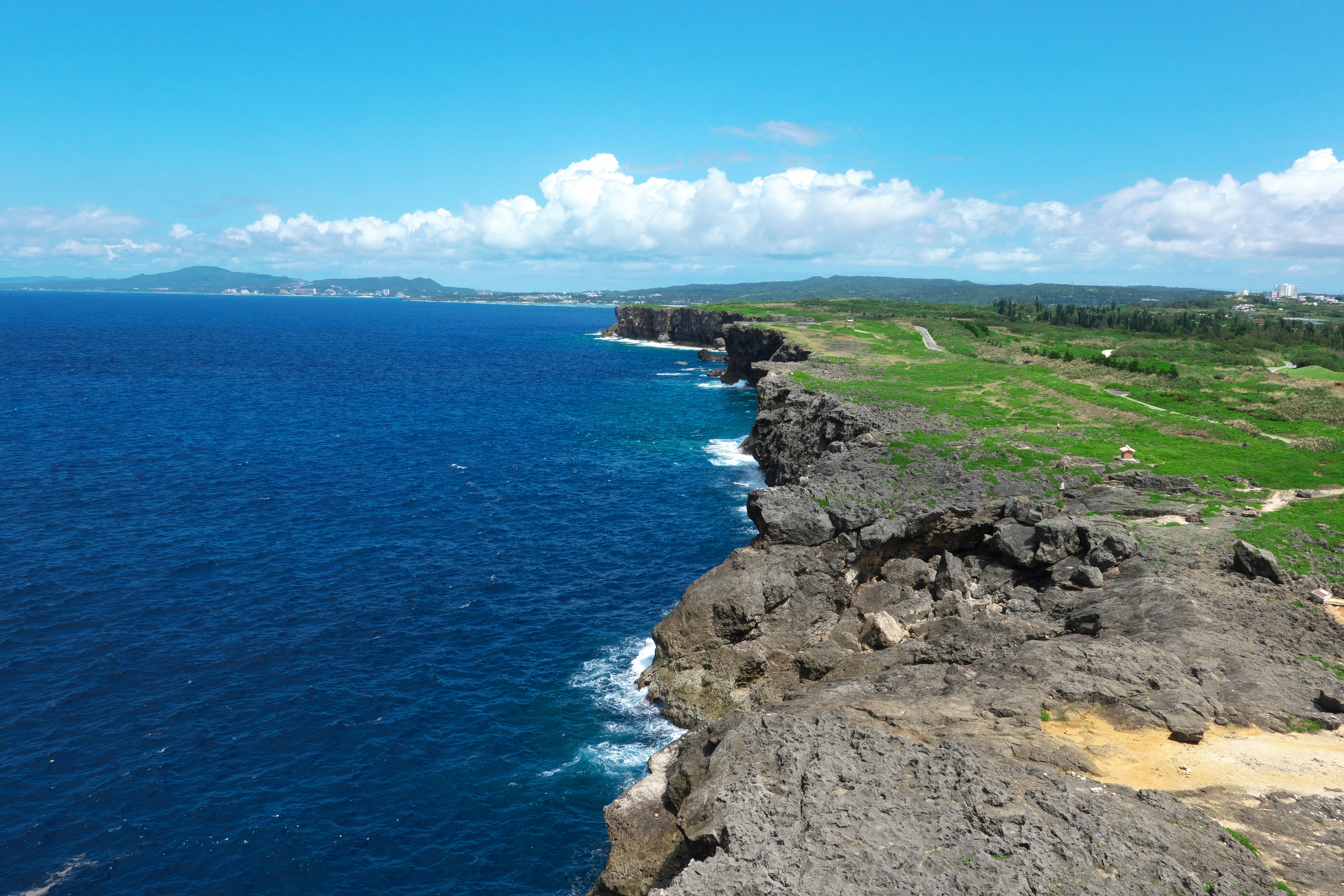 Rugged cliffs meet the blue ocean under a clear sky.
