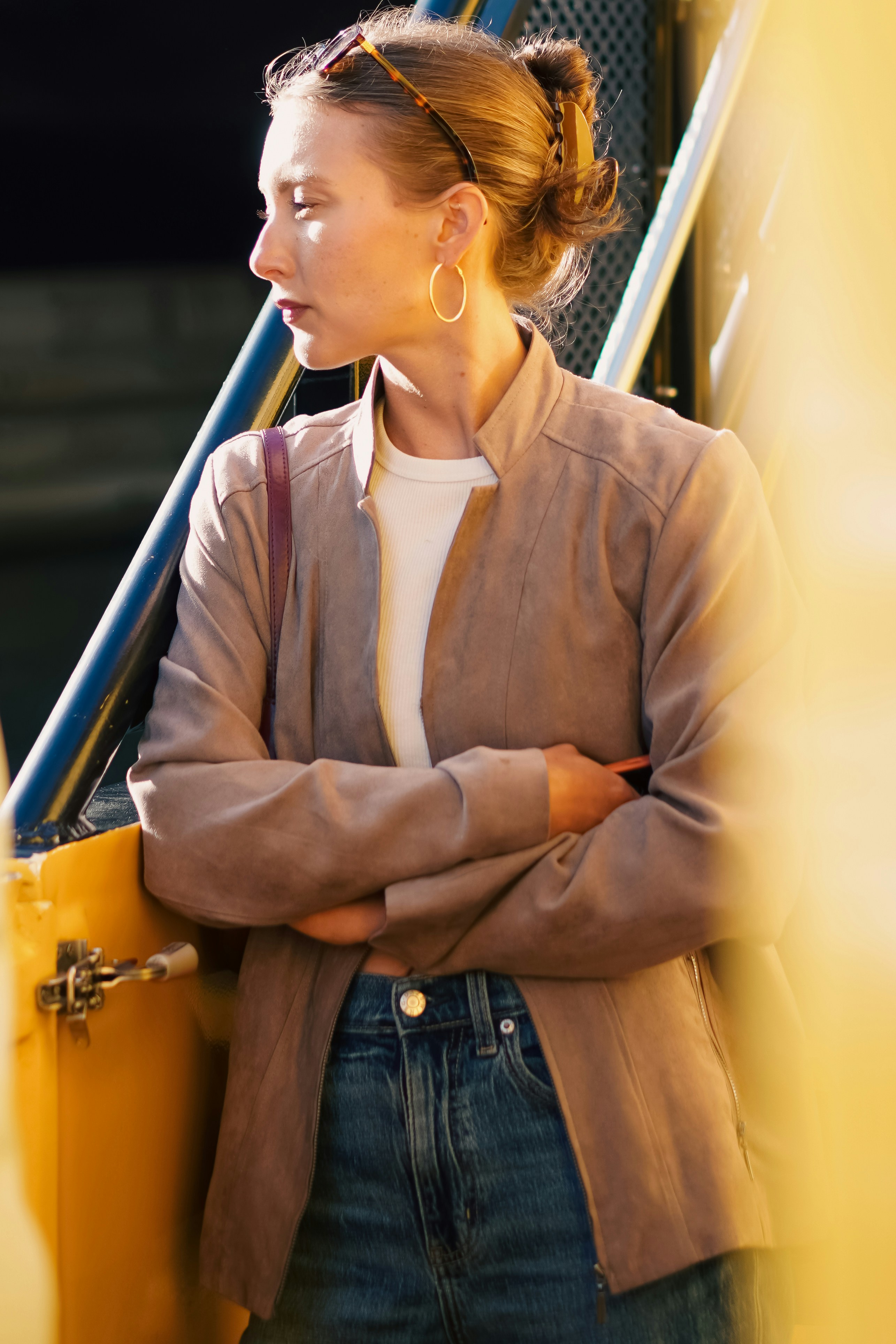 Crossed arms, sunlit silhouette: street style by the staircase