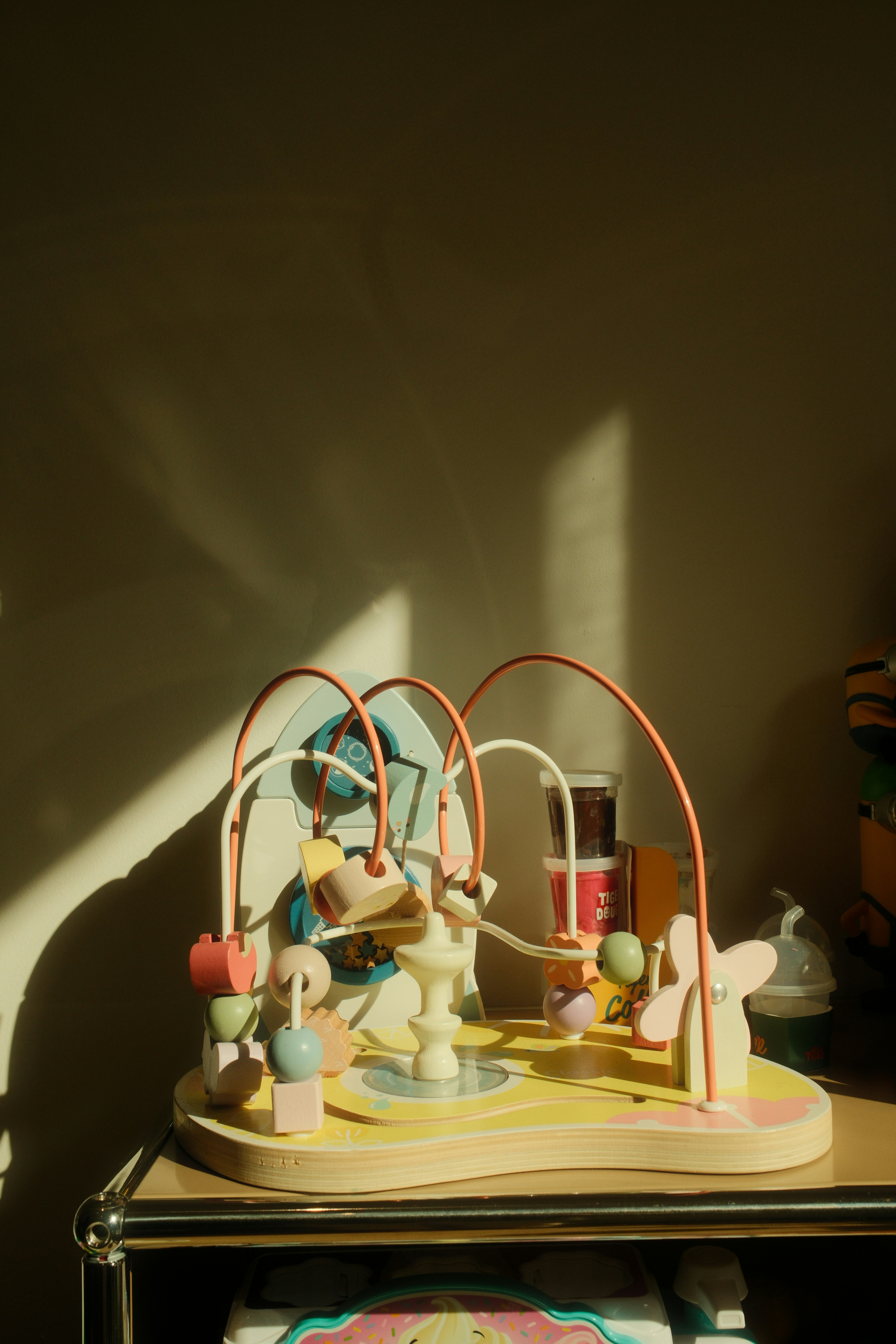A colorful wooden bead maze toy bathed in sunlight.
