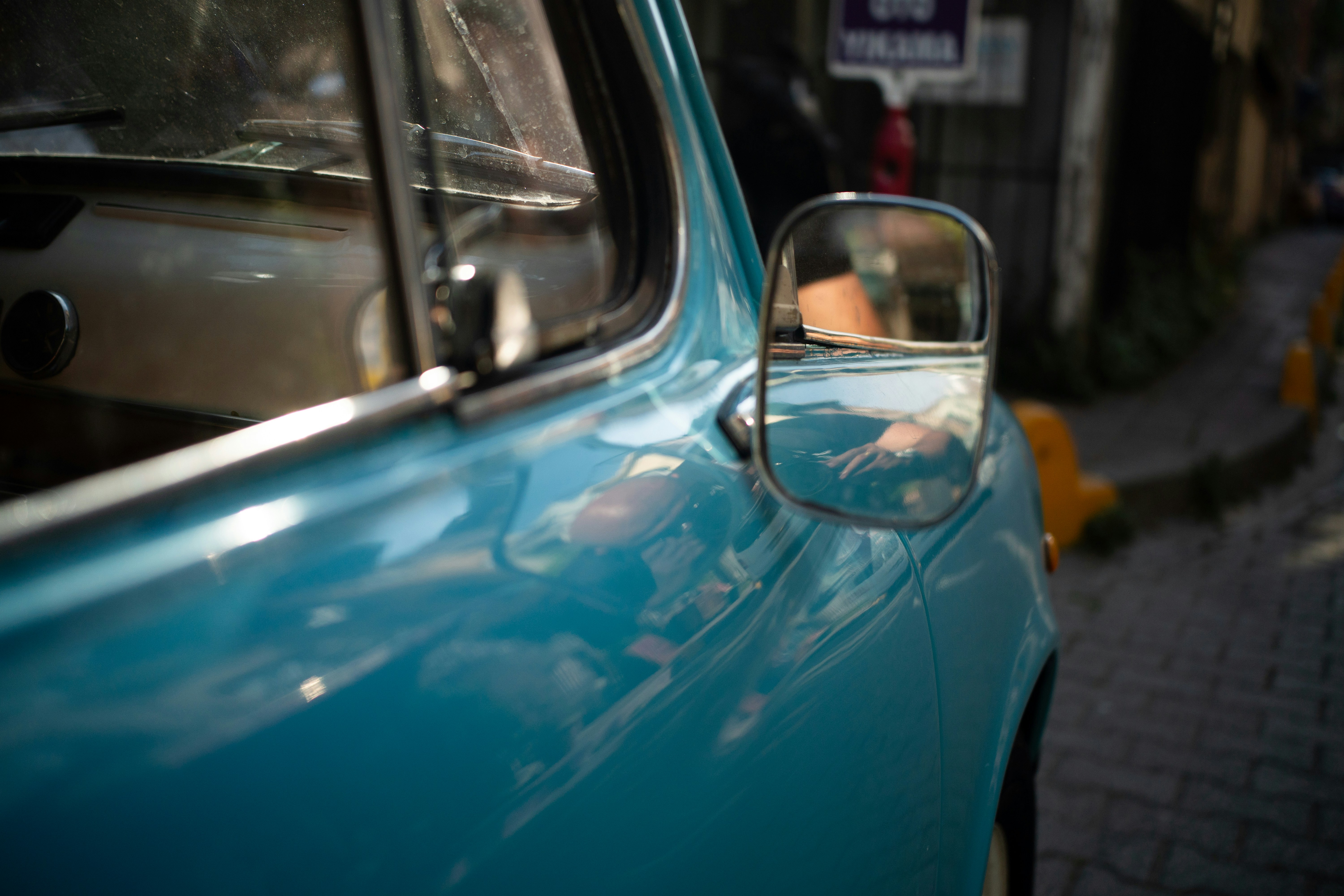 Shiny blue vintage car's side and rearview mirror.