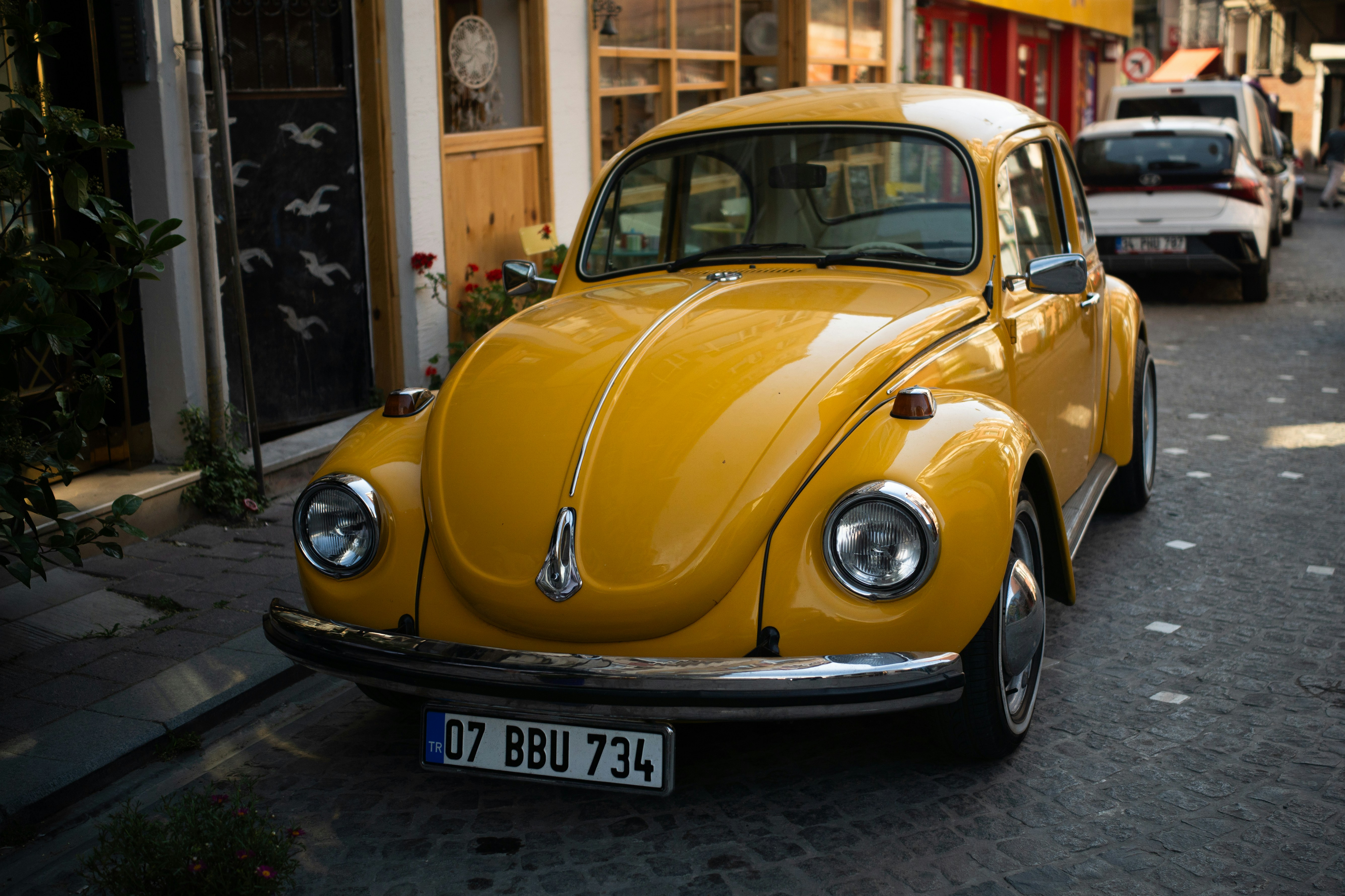 Yellow classic volkswagen beetle parked on a city street.