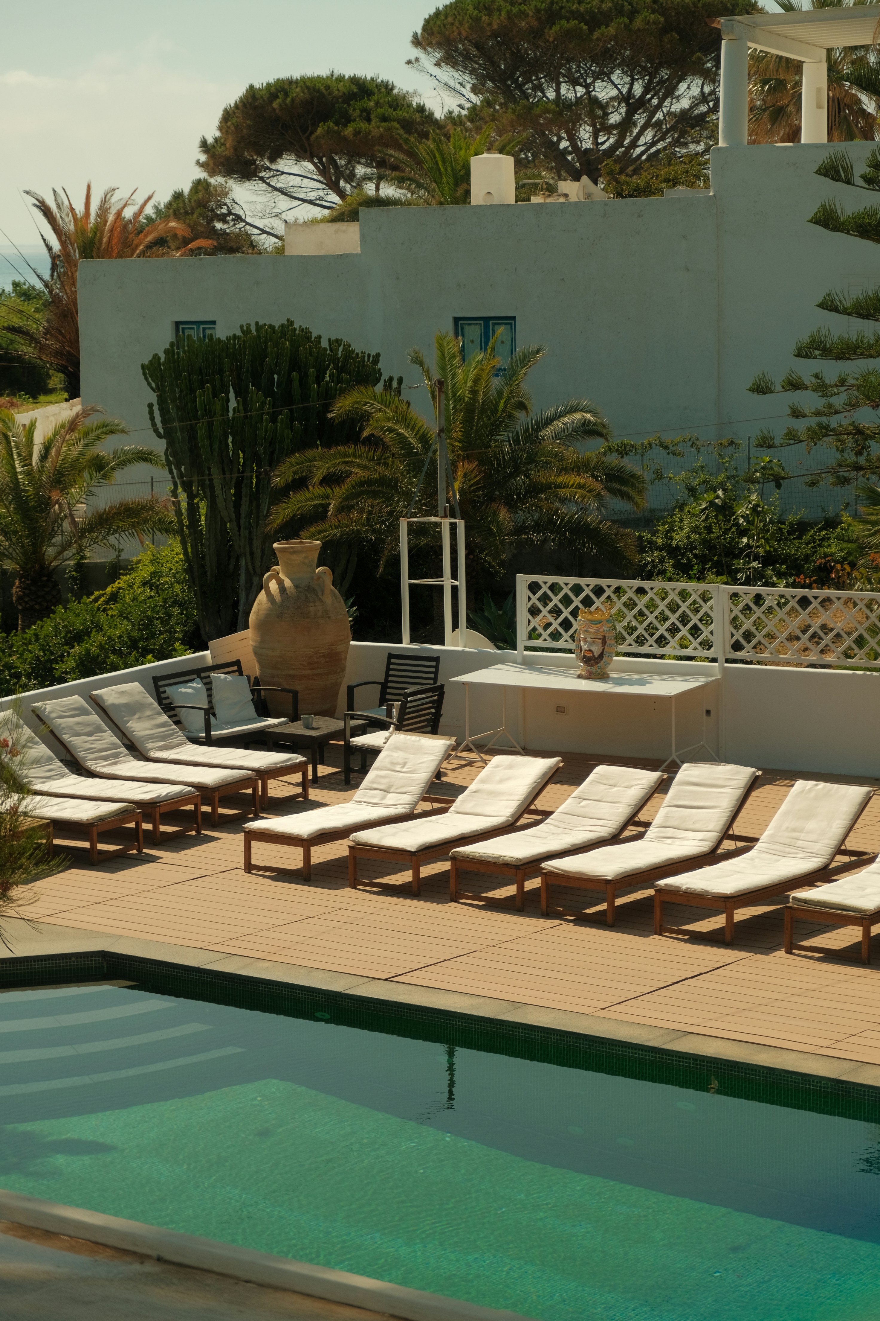 Resort swimming pool with sunbeds and lush greenery.