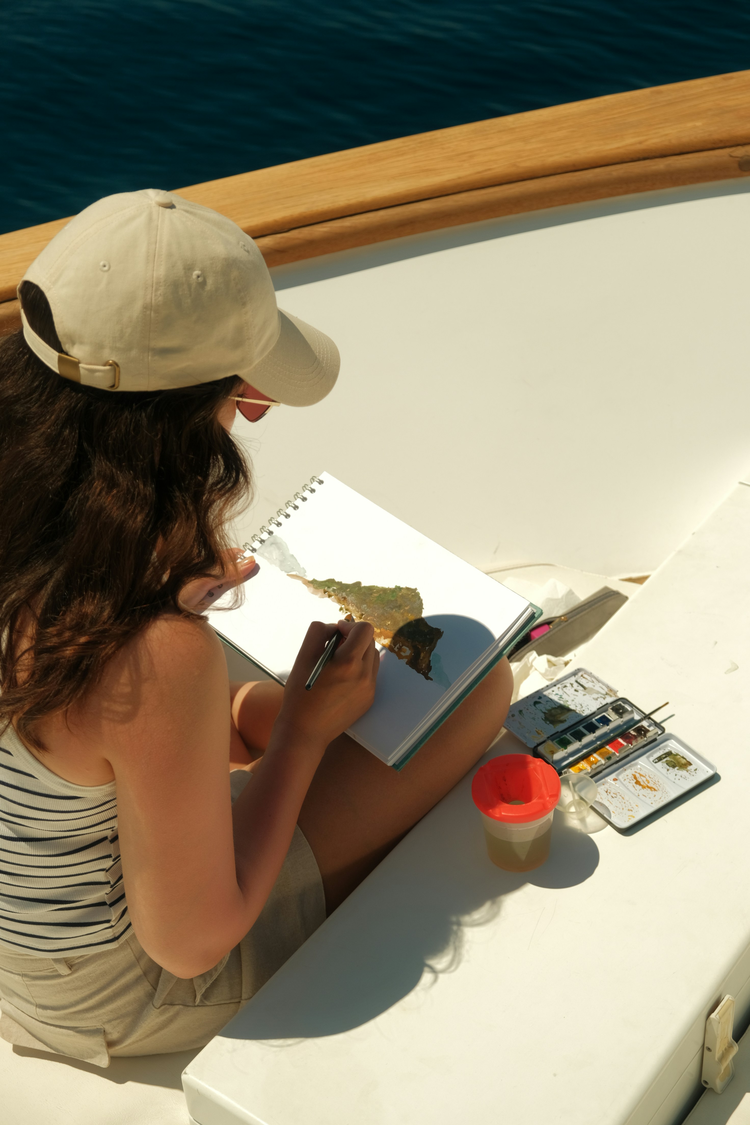 Sketchbook under sun: a girl sketches aboard a sunlit boat