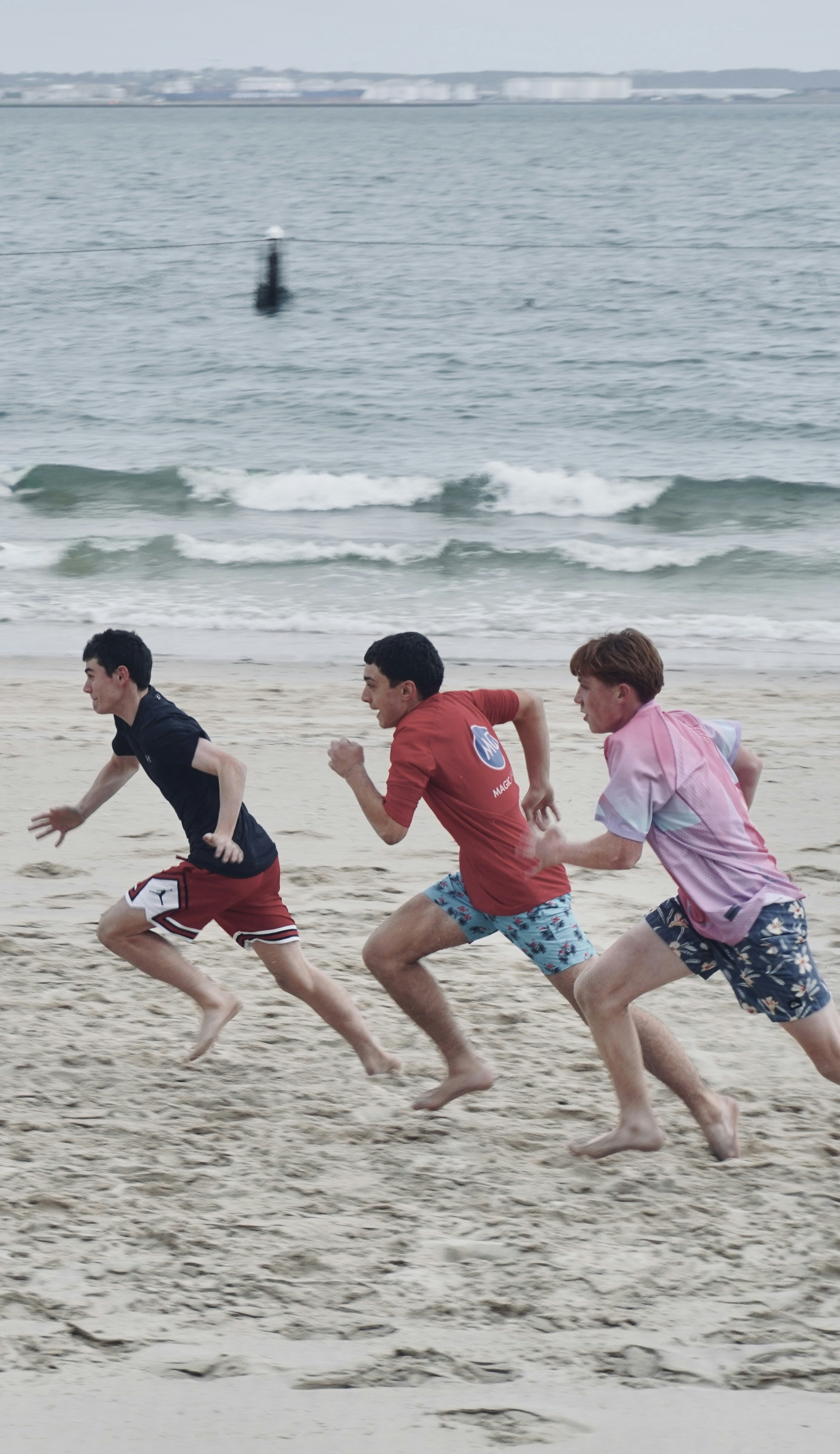 Three friends sprinting along a sunlit beach