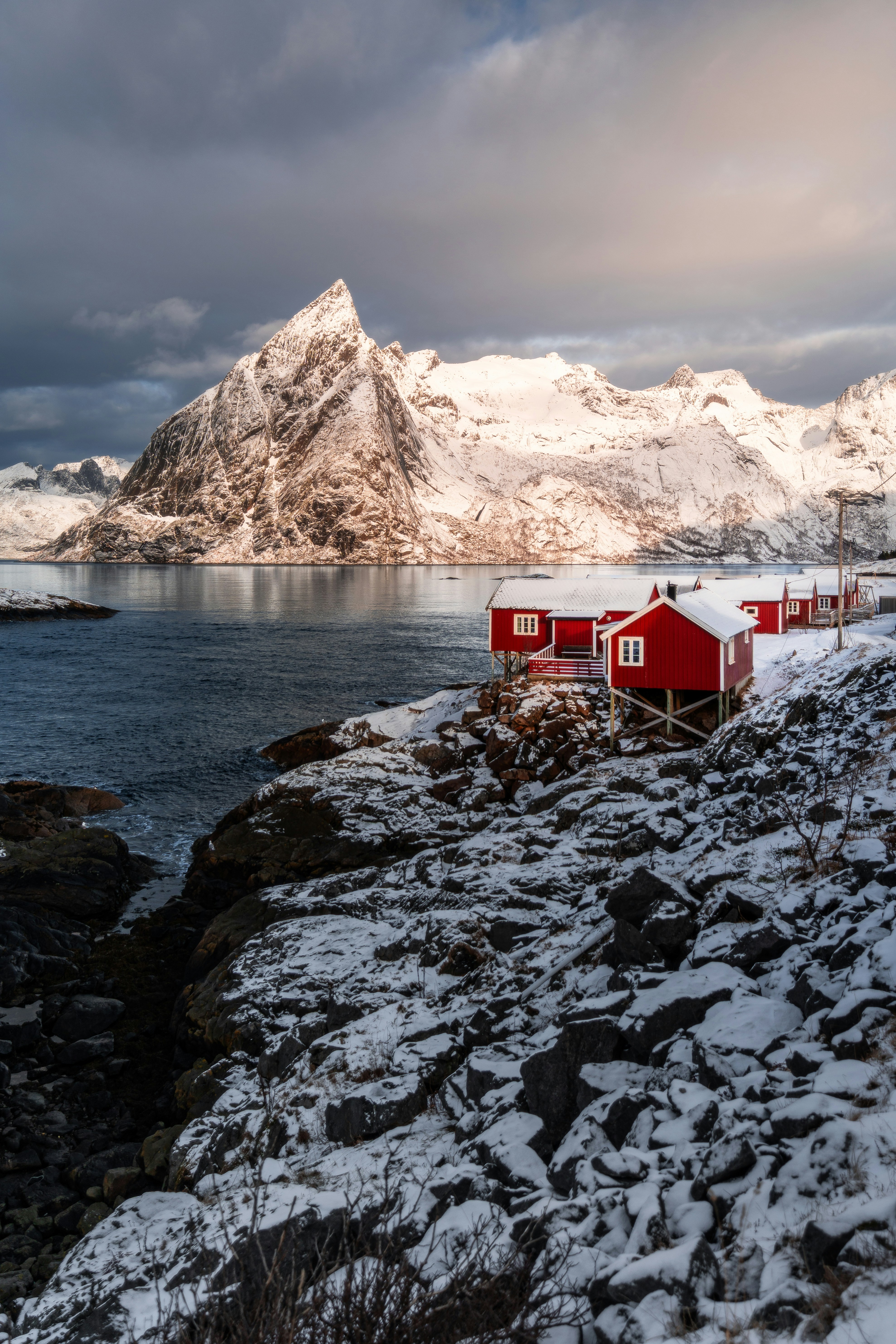 Red Dwellings Against Snow-Capped Peaks by Midnight Fjord