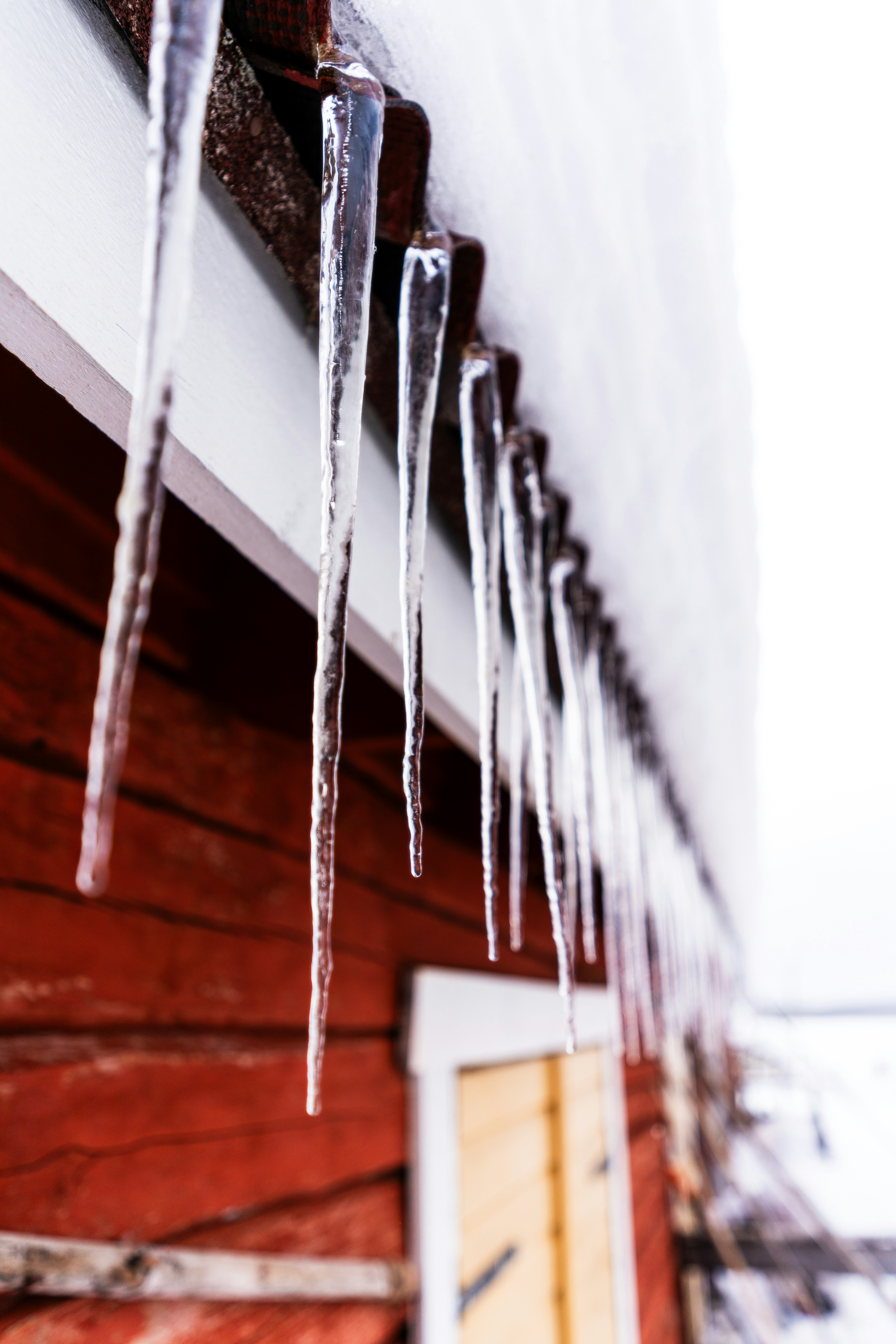 Icicle Army: Thin Ice Spears Clinging to a Rustic Snowbound Eave