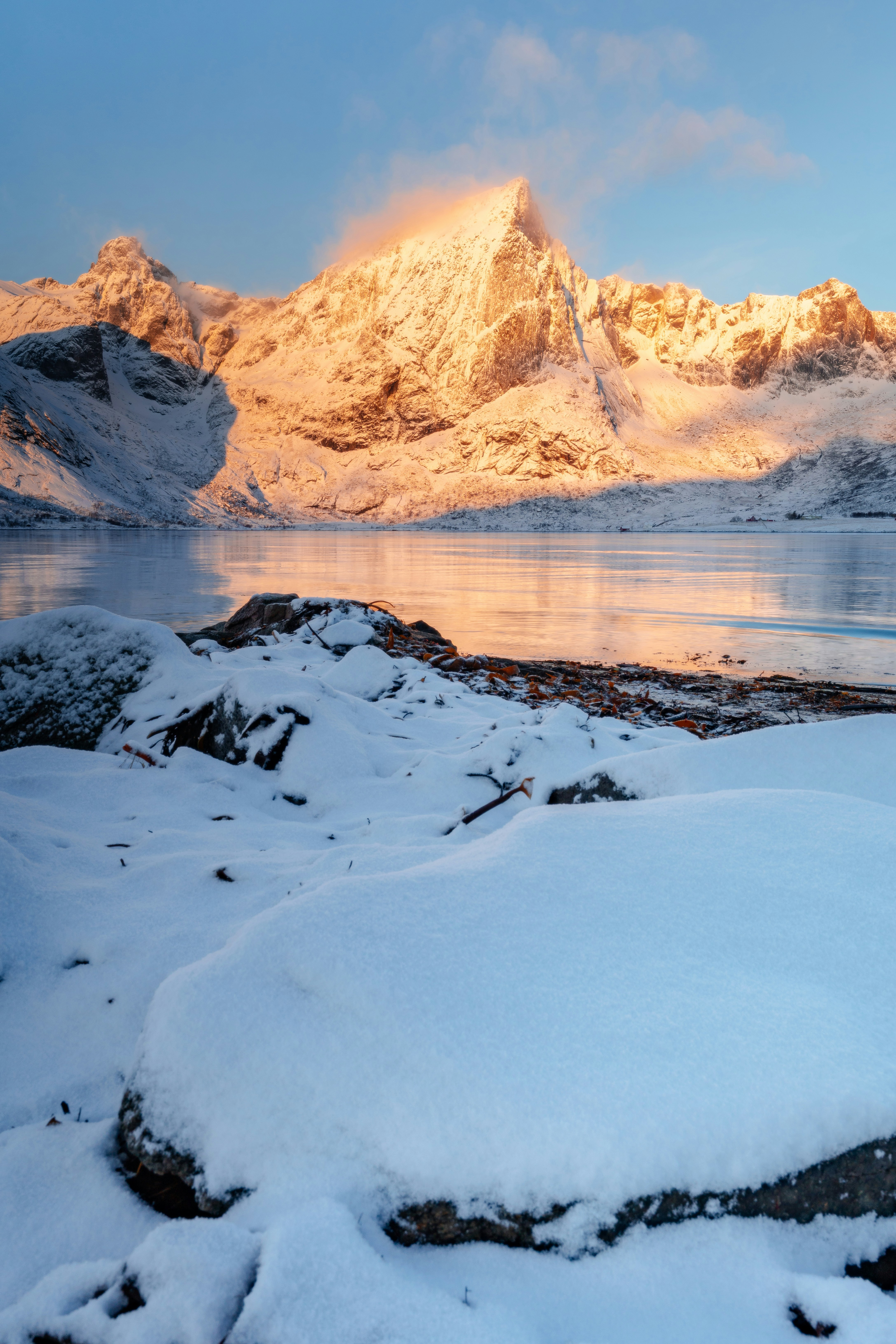 Alpenglow on jagged peaks over a frozen coastline