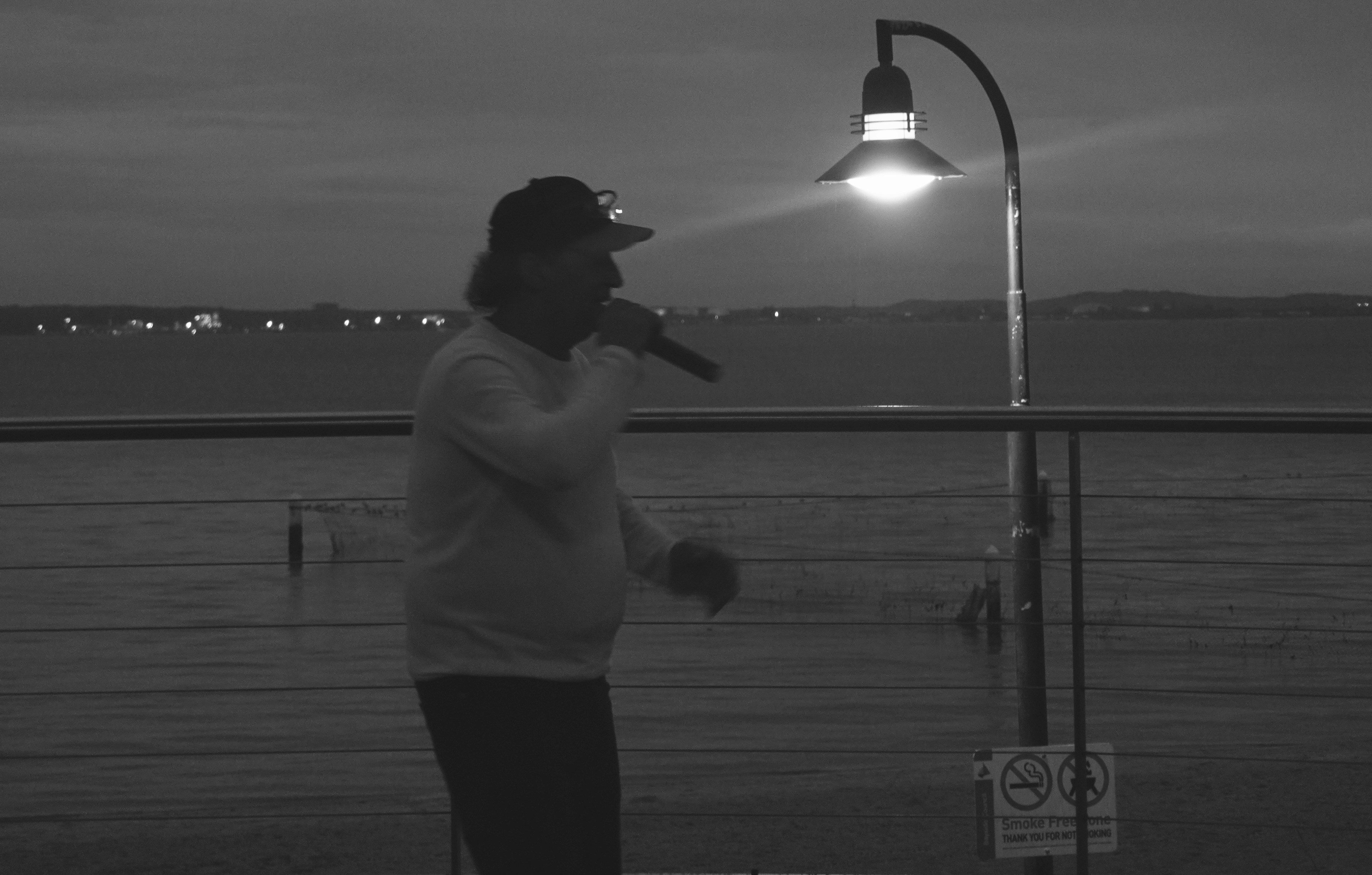 Midnight Mic: A Lone Performer Under the Pier Lamp