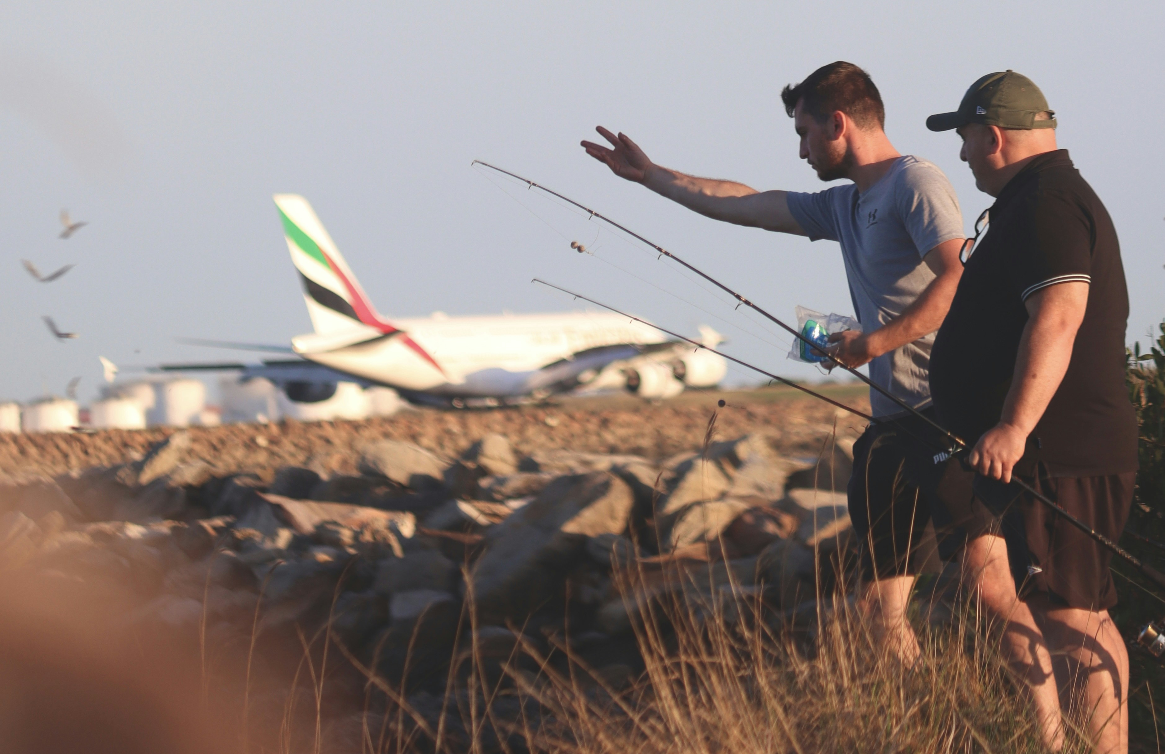 Toward the Shore: Anglers and a Distant Jet in the Golden Light