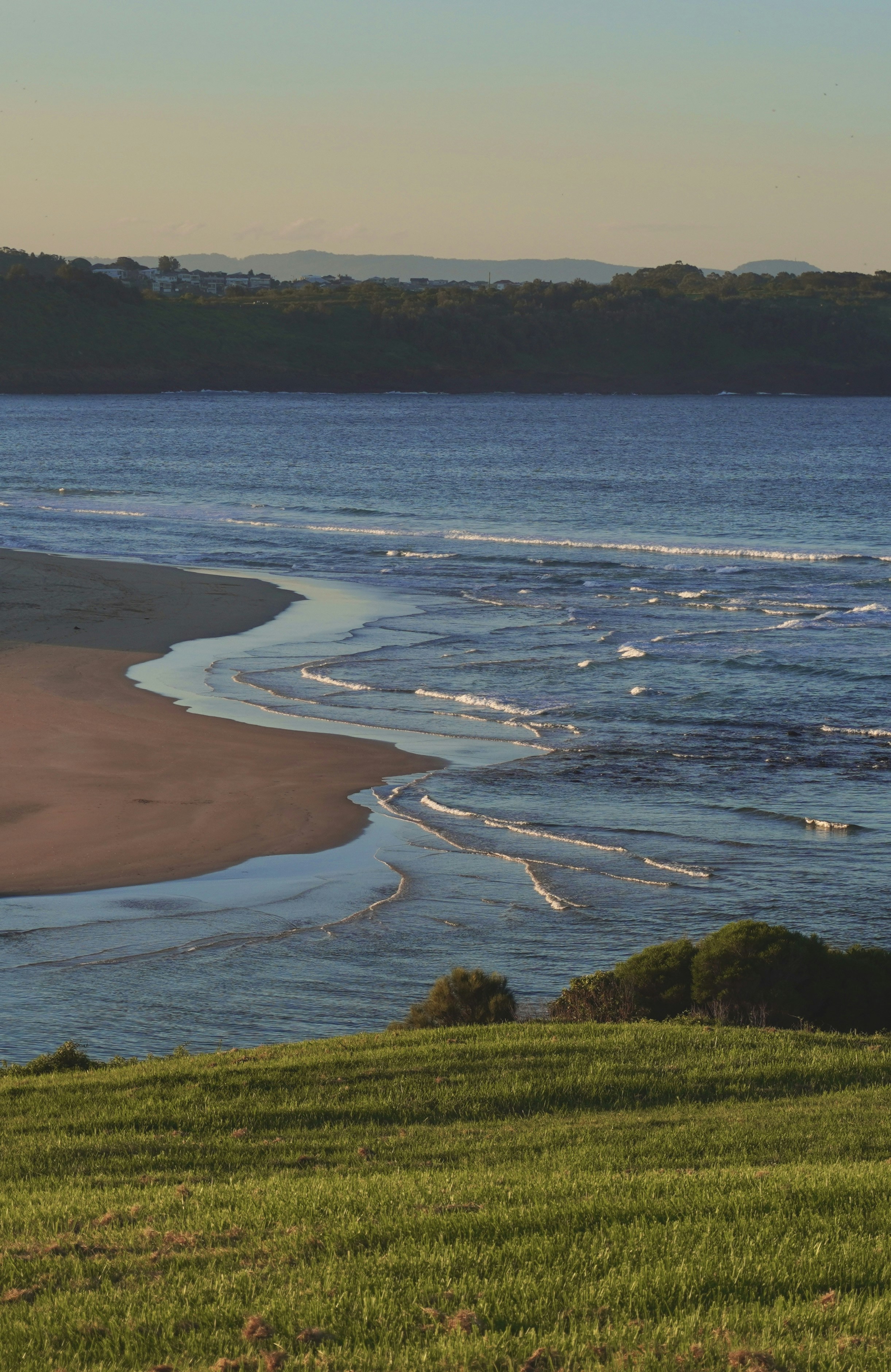 Sunlit Shoreline: grassy foreground meeting a calm Atlantic horizon